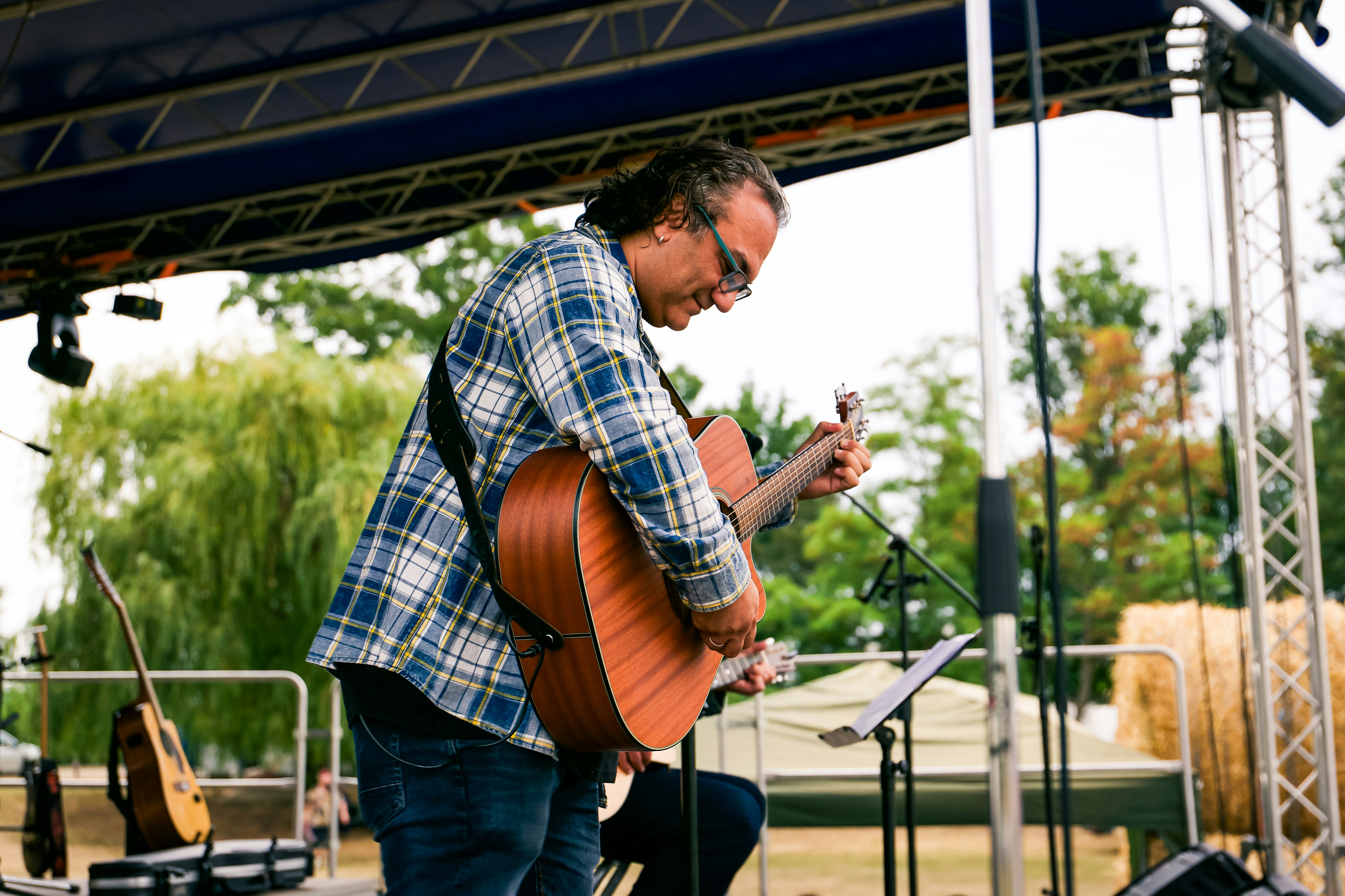 Guitarist in Mid-Performance: Studio-Blue Backdrop on Open-Air Stage