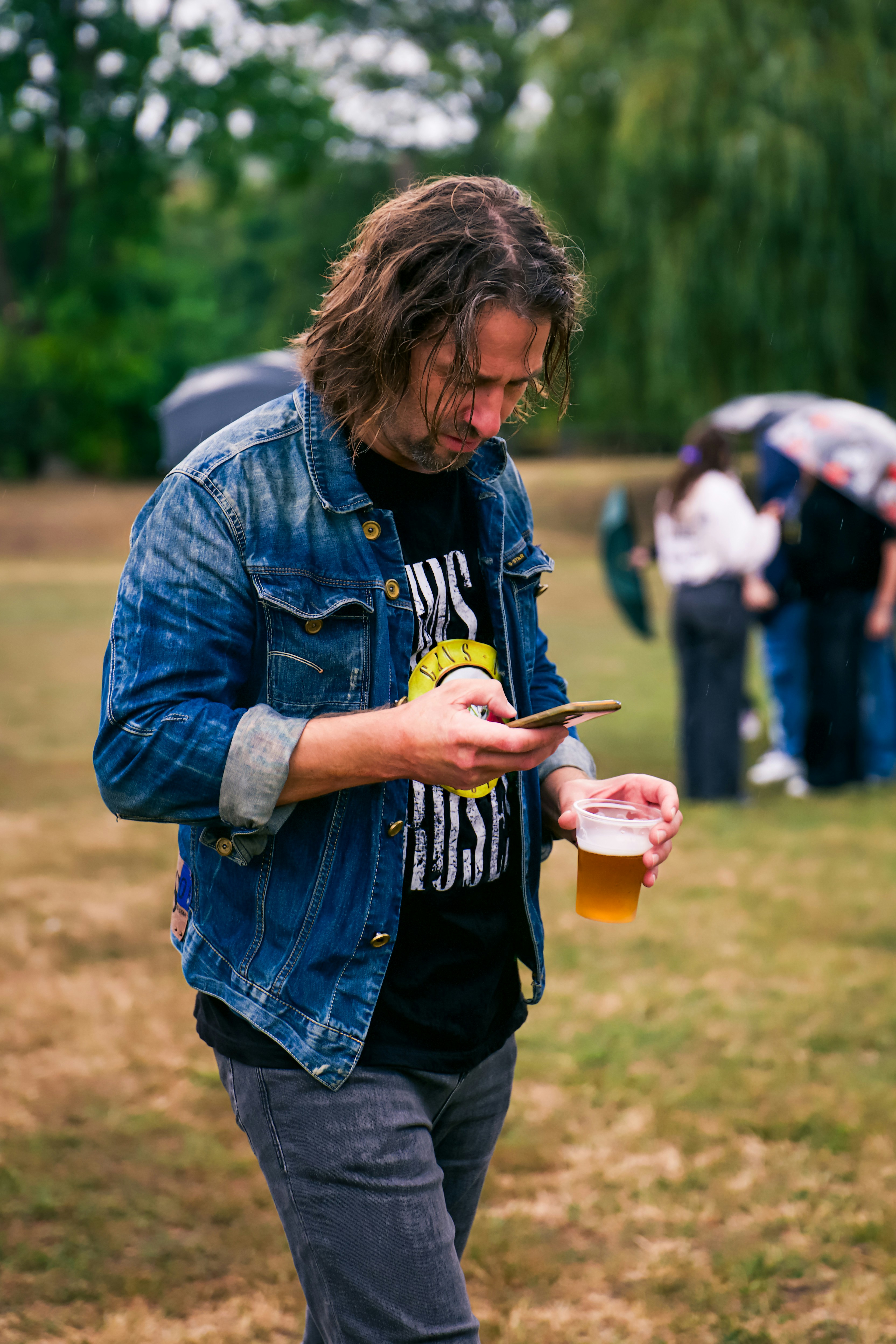 Casual Conductor: Man in Denim Tints a Friendly Beat at a Park Gathering