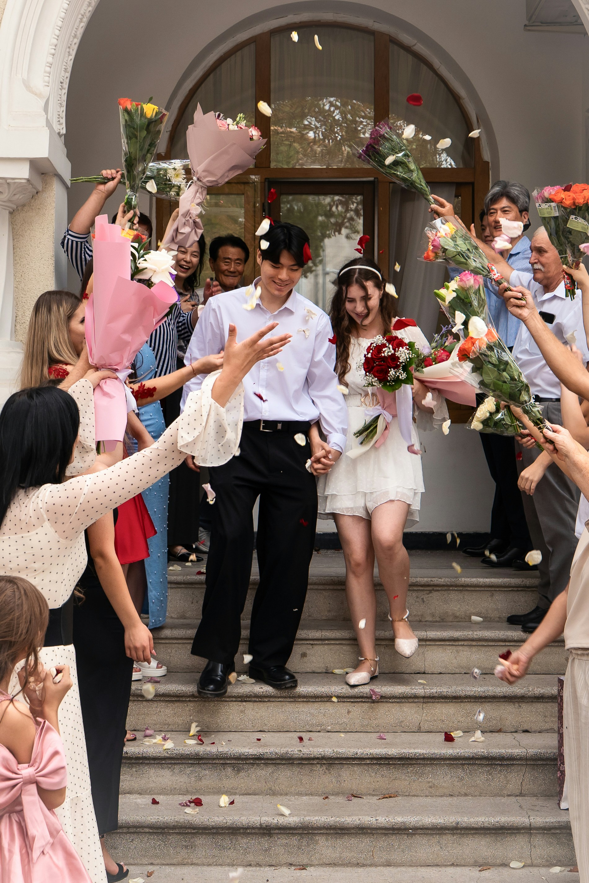 Stairway Exit: A Newlywed Walk Amid Celebratory Blooms