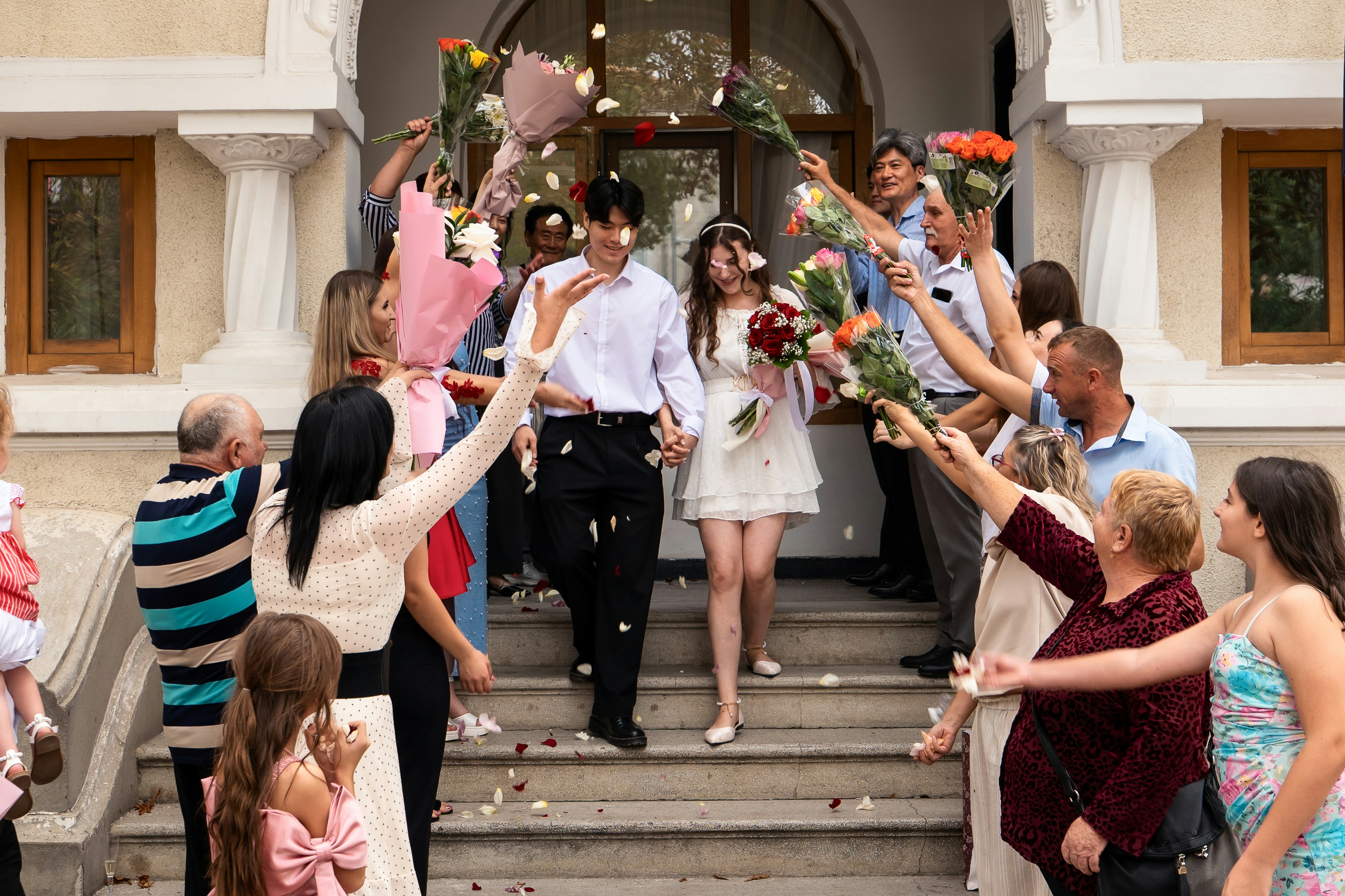 Celebration at the Steps: A Newlywed Exit Amid Cheering Guests