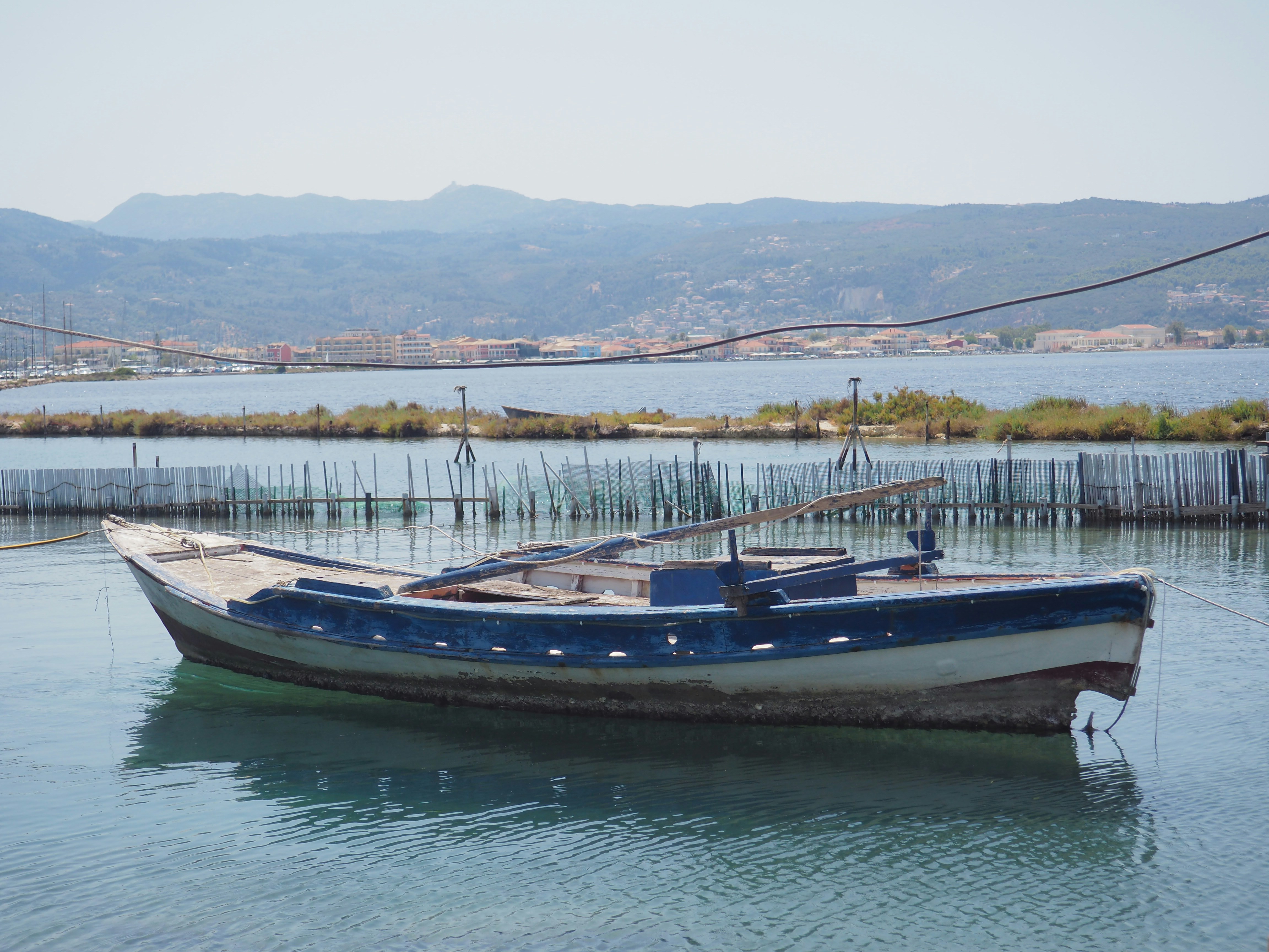 Blue Boat at Quiet Shore with Distant Low Hills