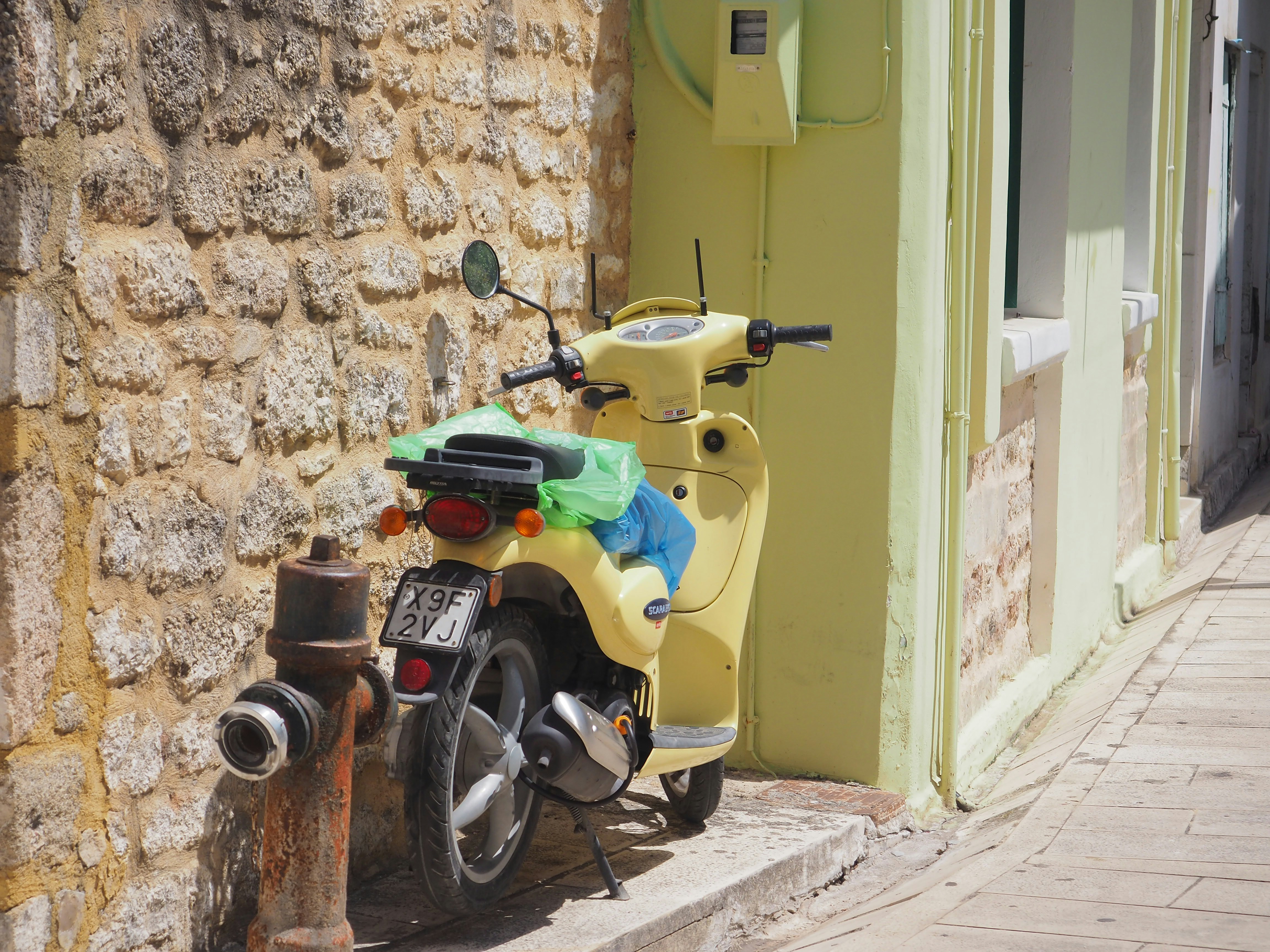 Sunny Vespa by the Stone Wall in a Narrow Mediterranean Street
