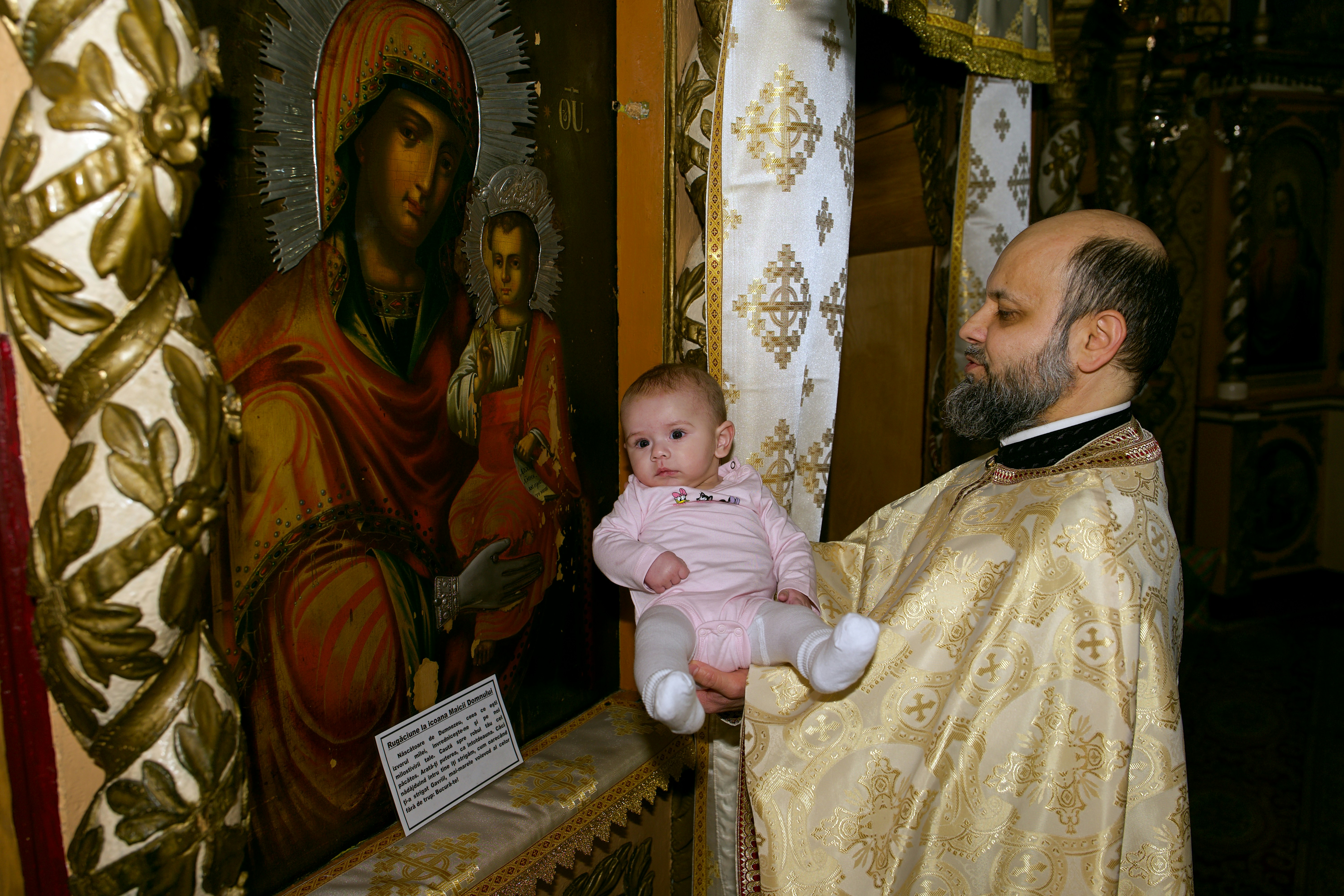Candlelit devotion: a priest presents a child before a religious icon