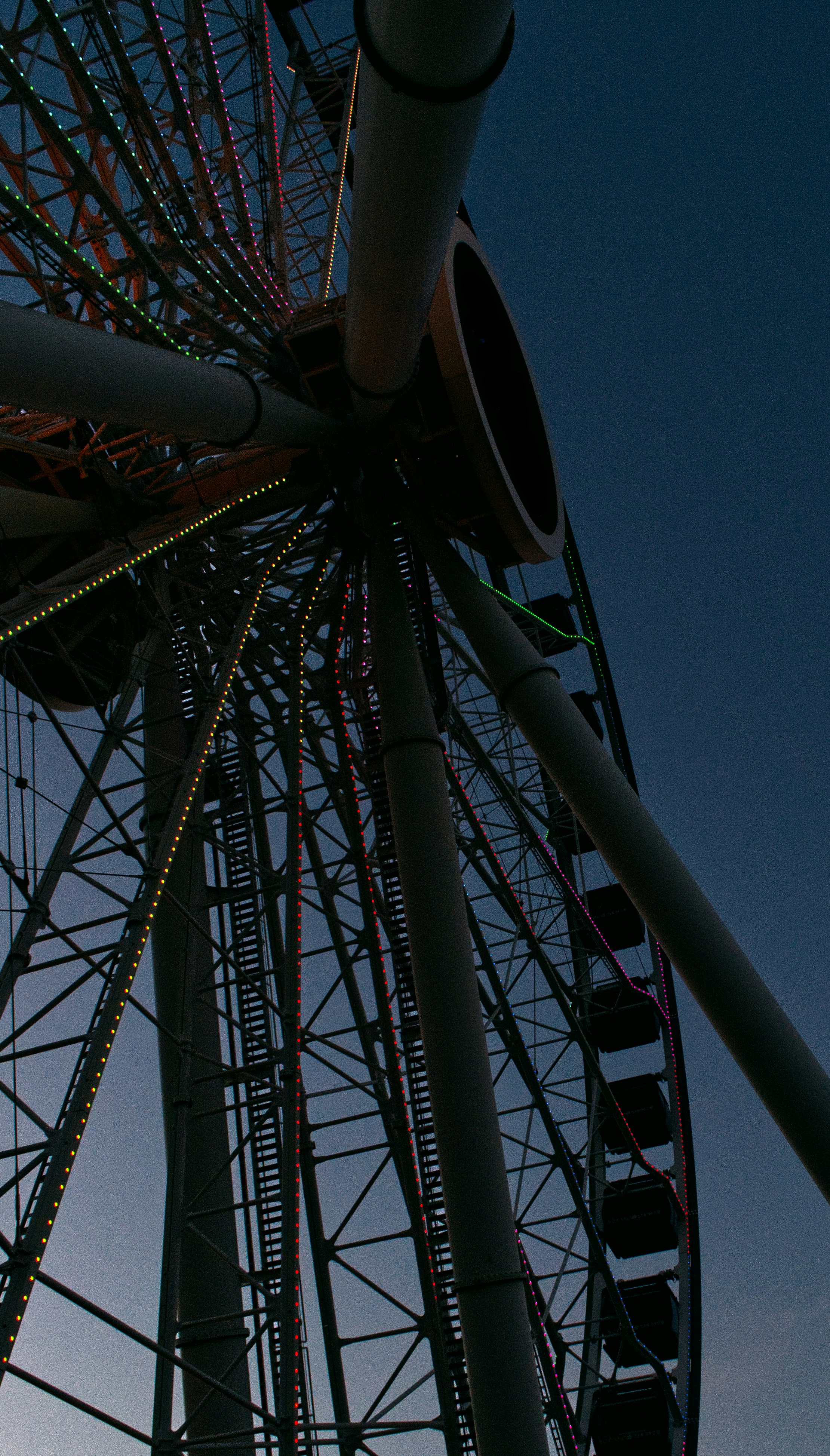Night-Cabled Giant: A Ferris Wheel Illuminated Against Twilight Steel