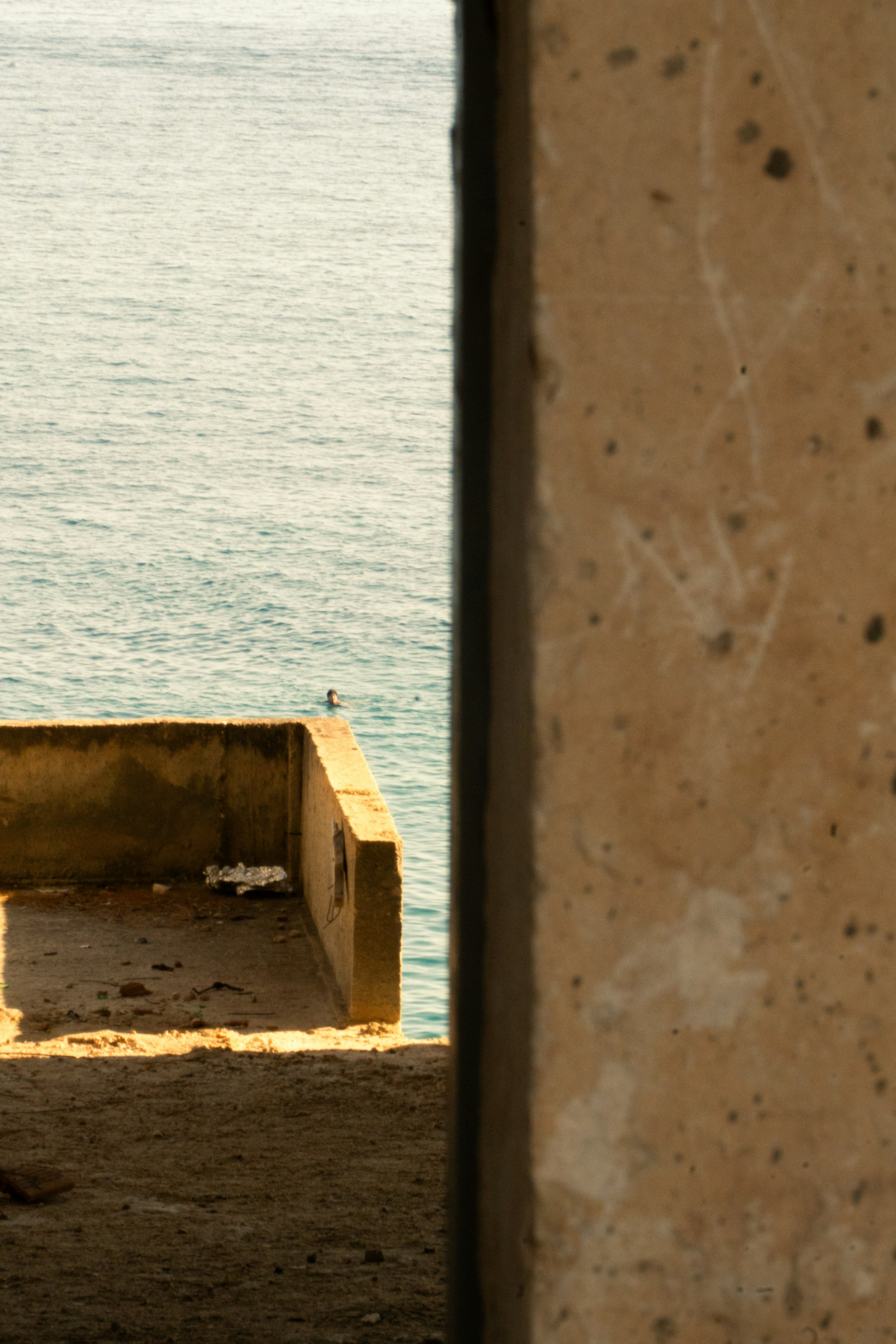 A Lone Figure at the Pier Edge Through Concrete Slats