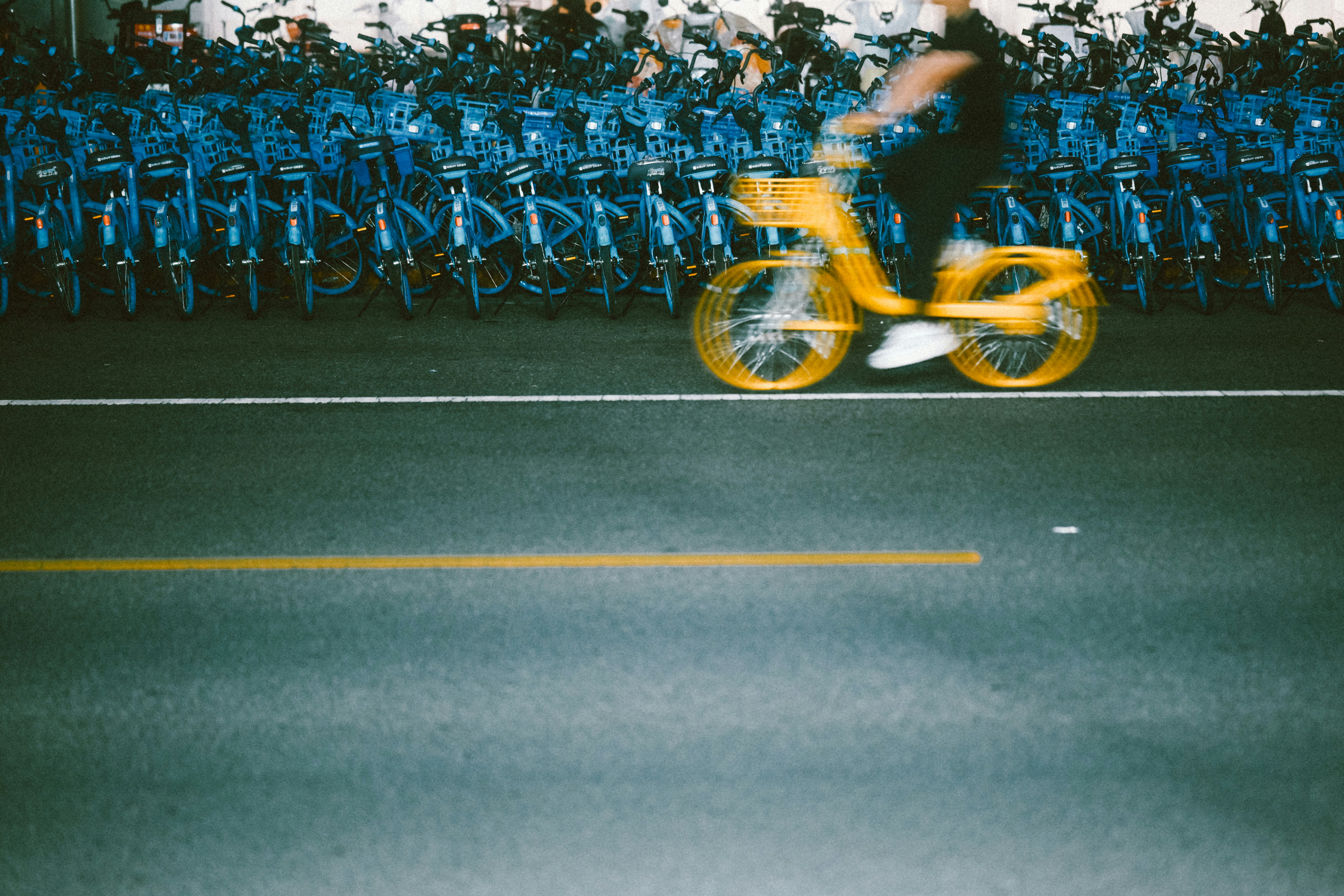 Rider in Motion: A Burst of Yellow Through a Sea of Blue Bikes