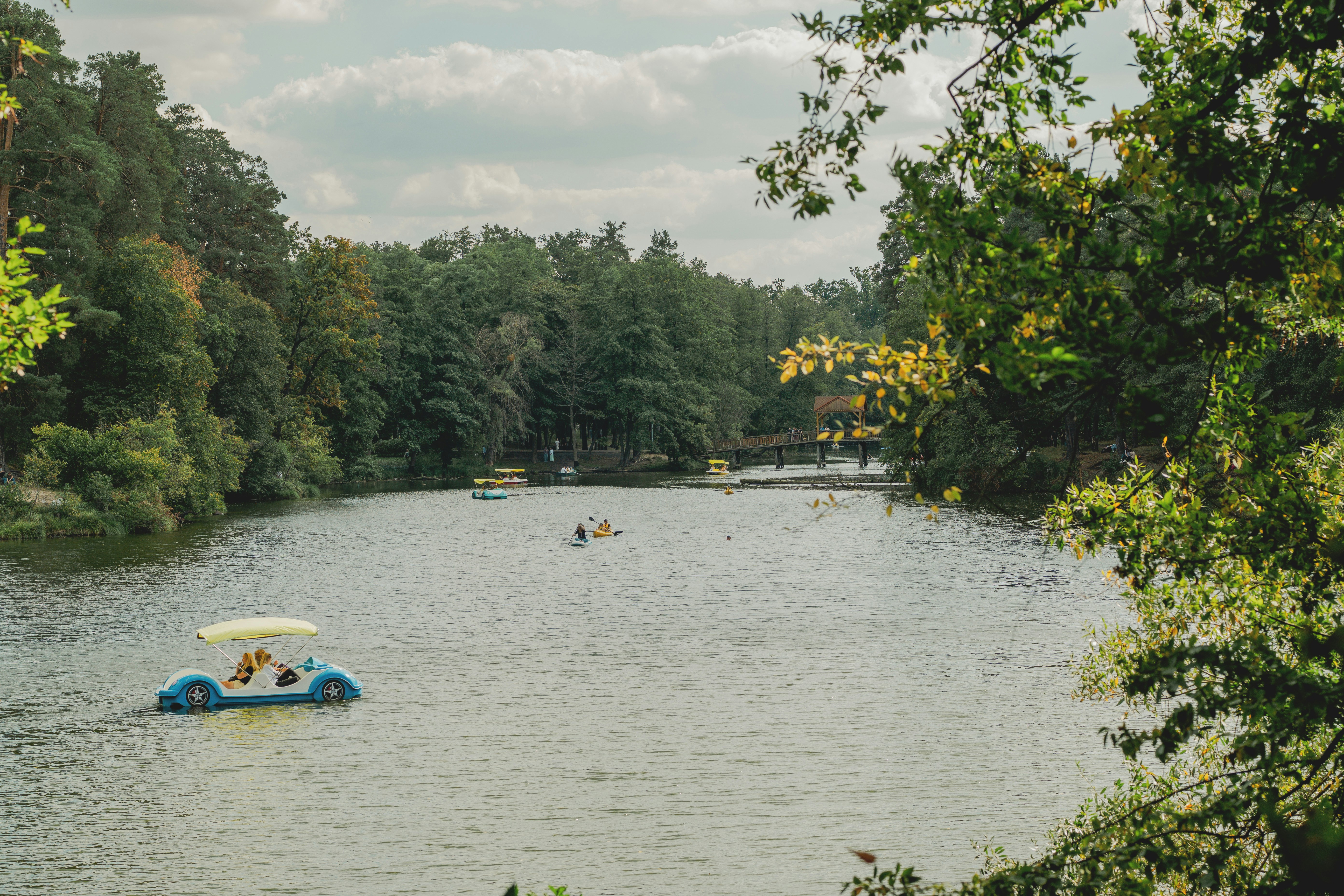 Blue pedal boat gliding through a sunlit lake arc