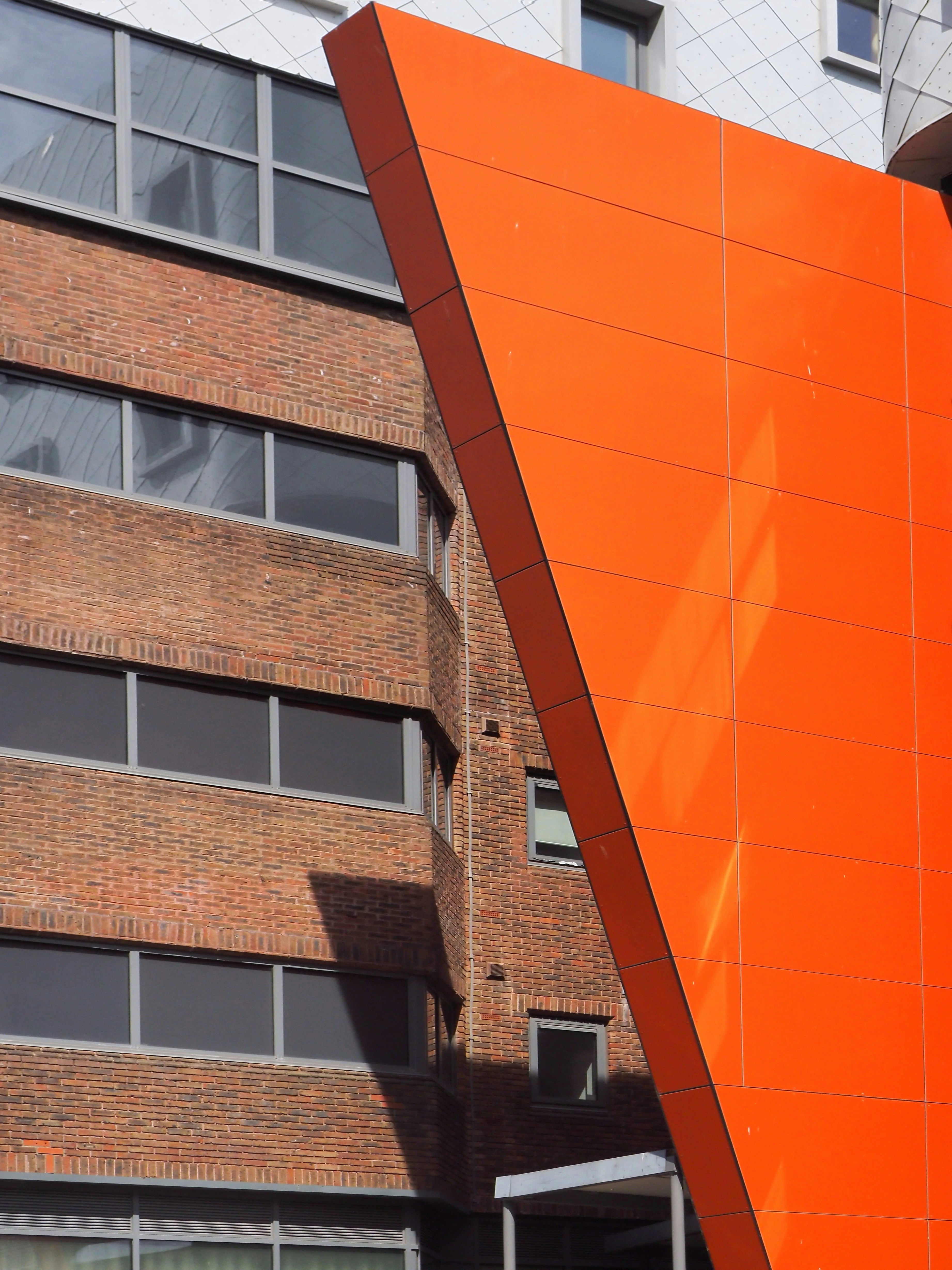 Bolt of Orange: Modern Facade Cuts Through Brick Geometry
