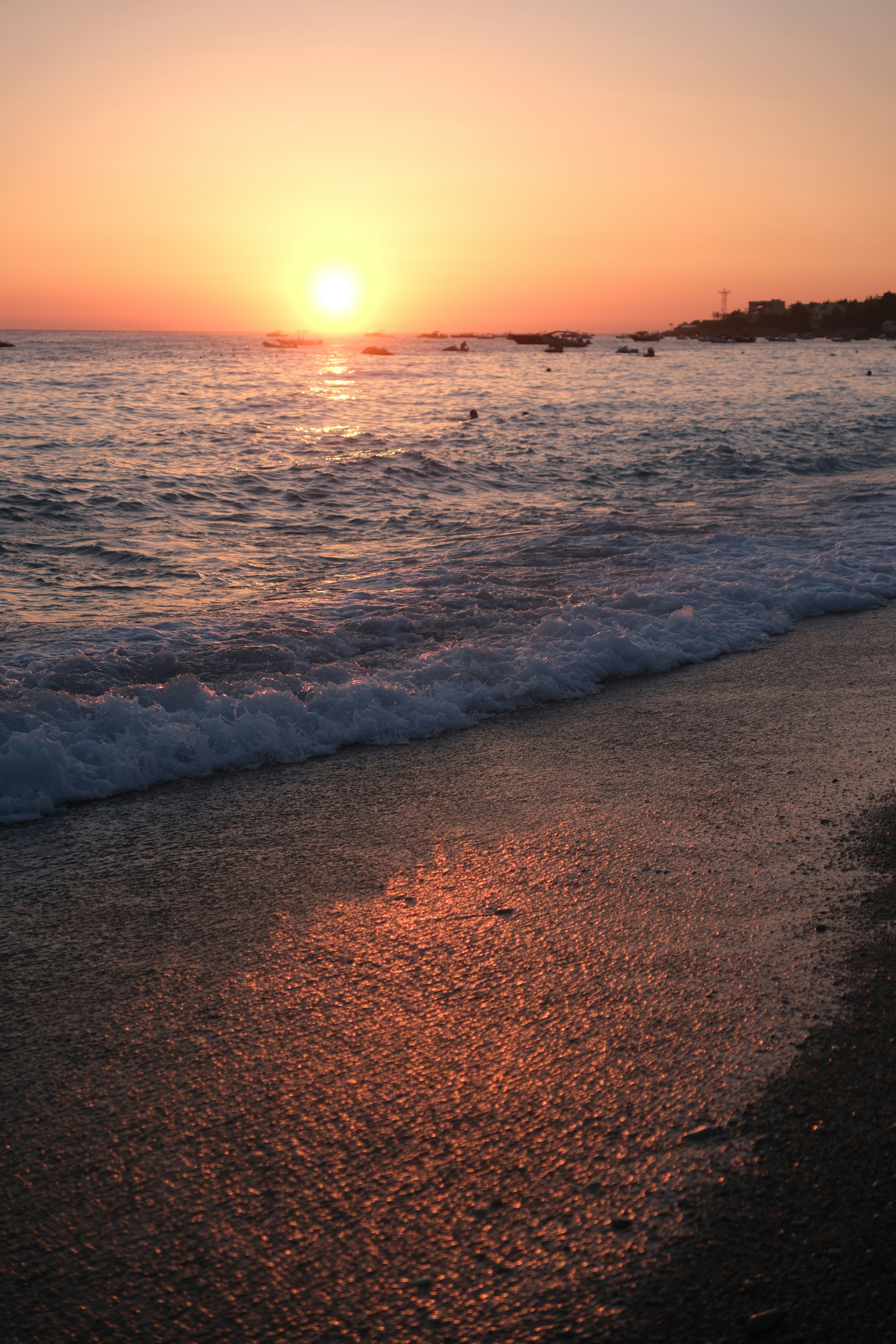 Sunlit Shoreline: Gentle Waves and Fiery Horizon