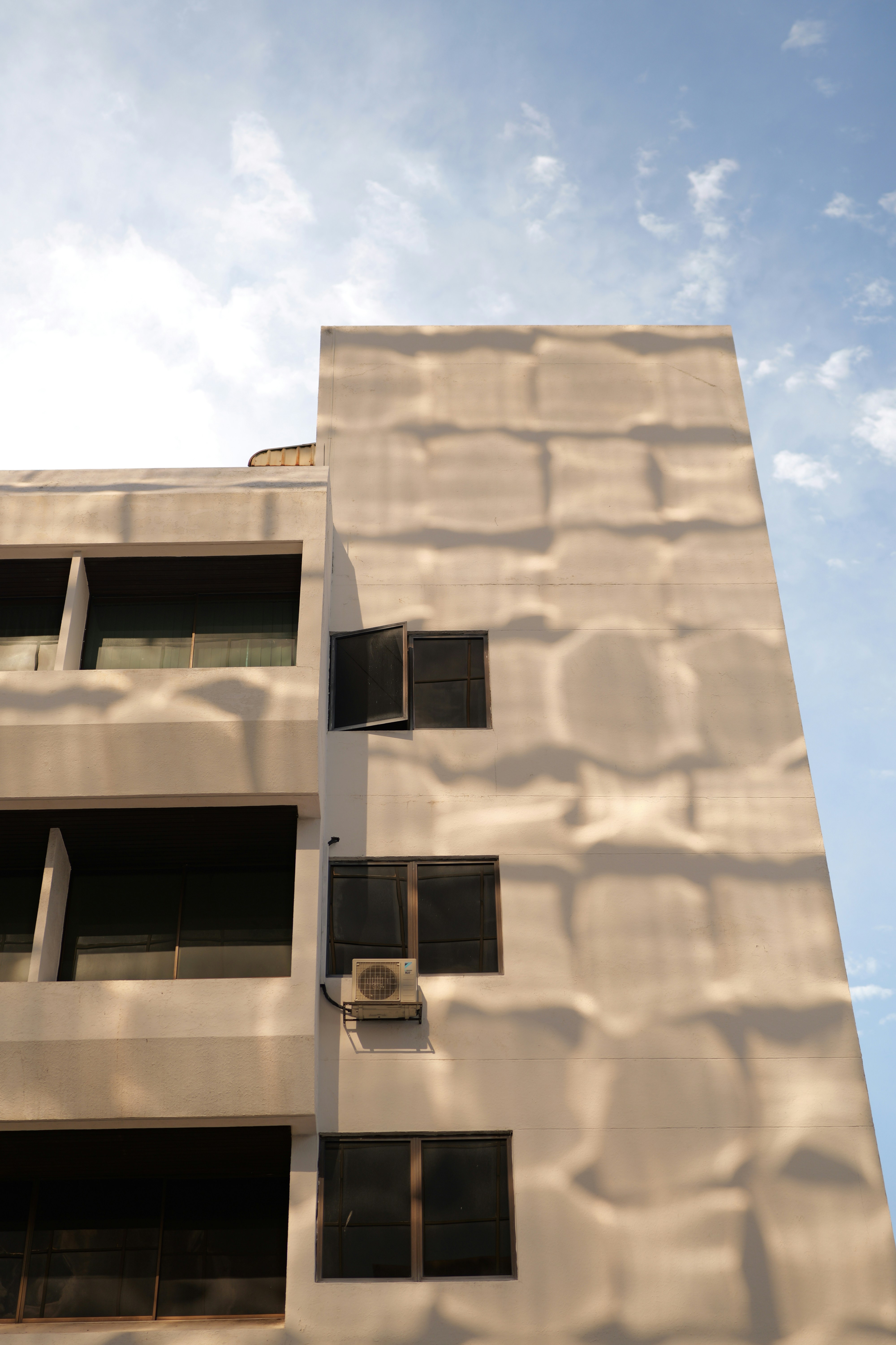 Sunlit Facade with Rippled Shadows on a Modern Block