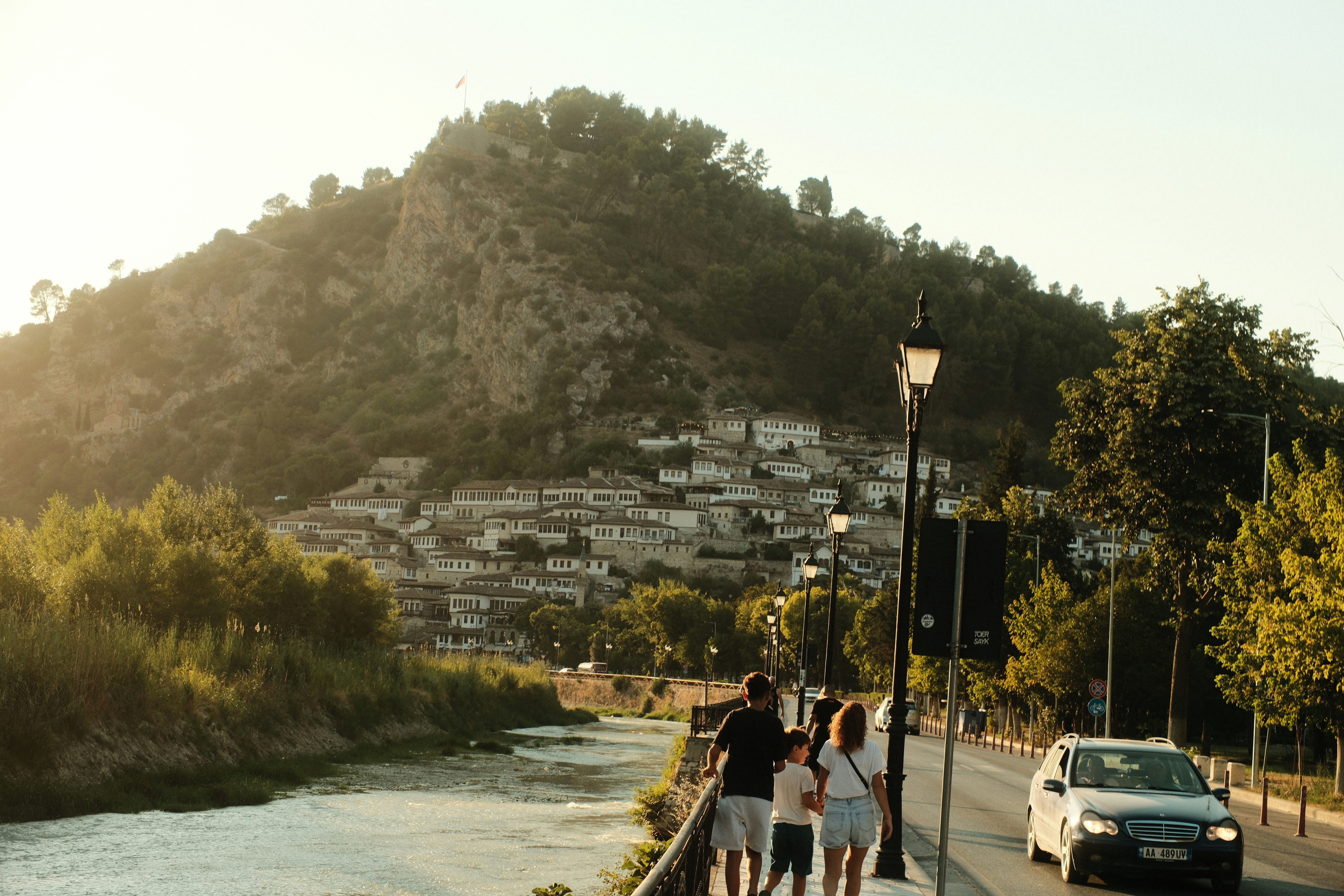 Sunlit hillside village along a riverside promenade