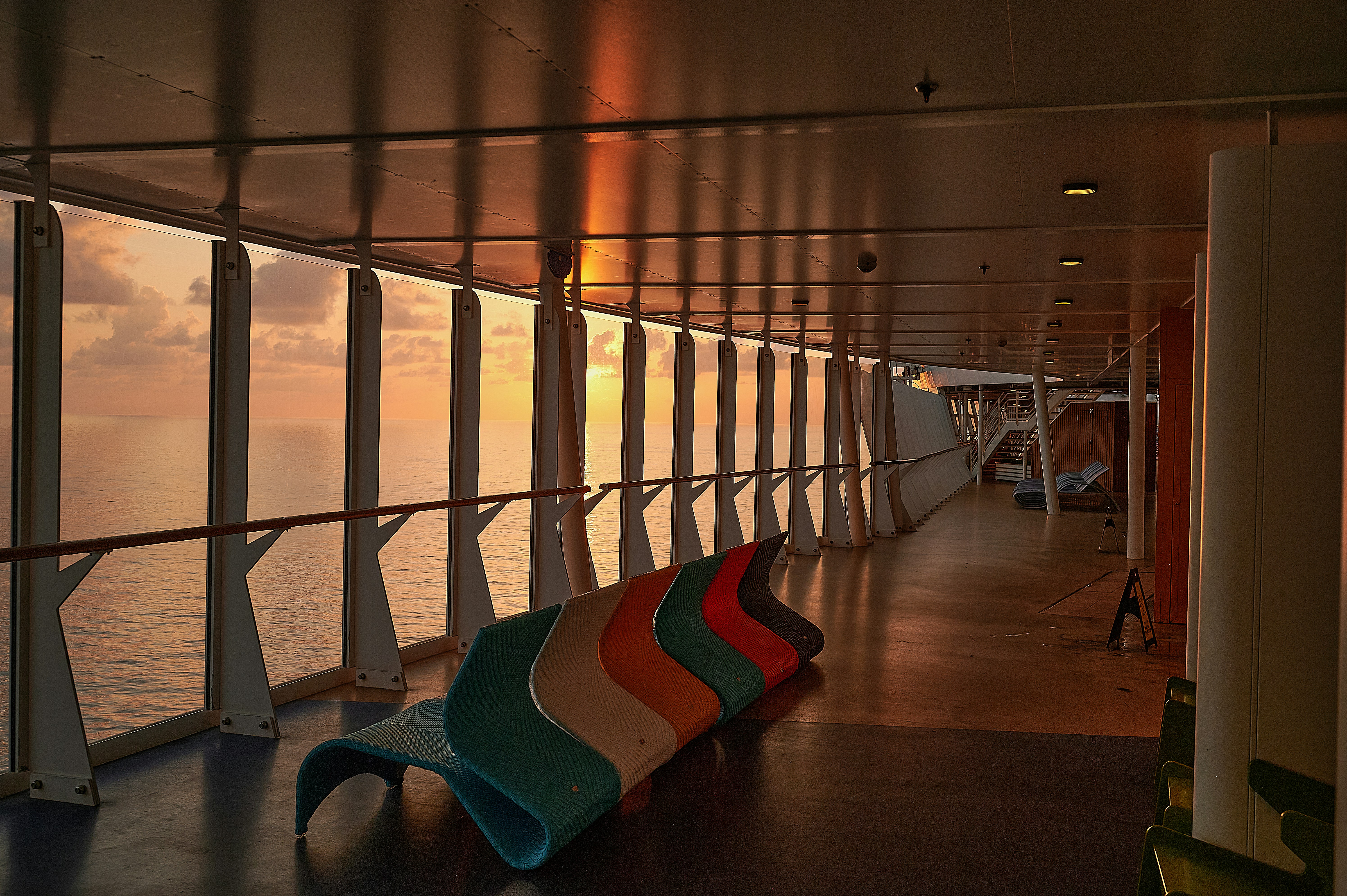 Sunset Corridor: Colored Deck Chairs Along a Cruise Ship Walkway