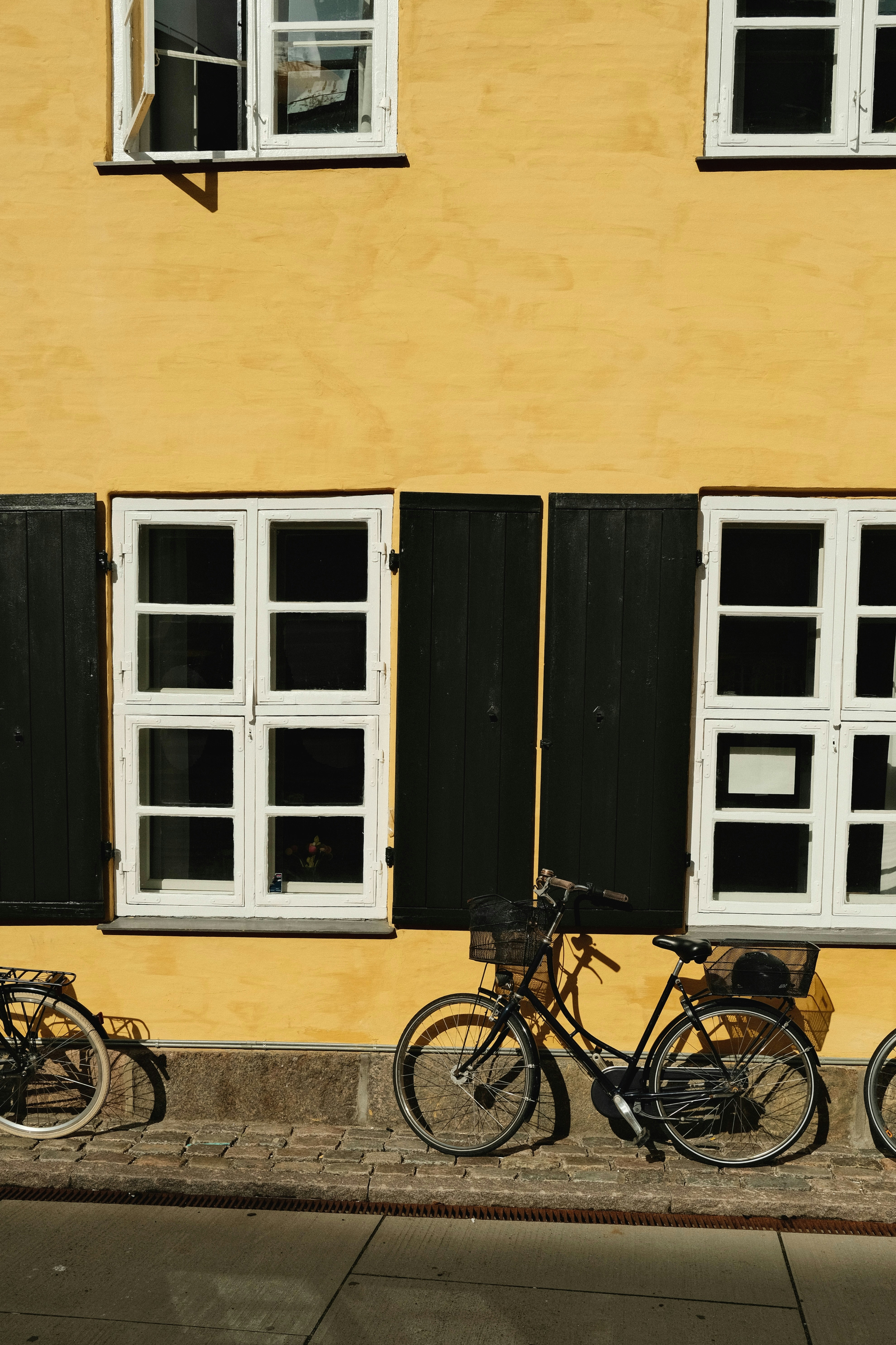 Yellow Facade, Quiet Streets: Bicycles Lean Against a Warm Wall