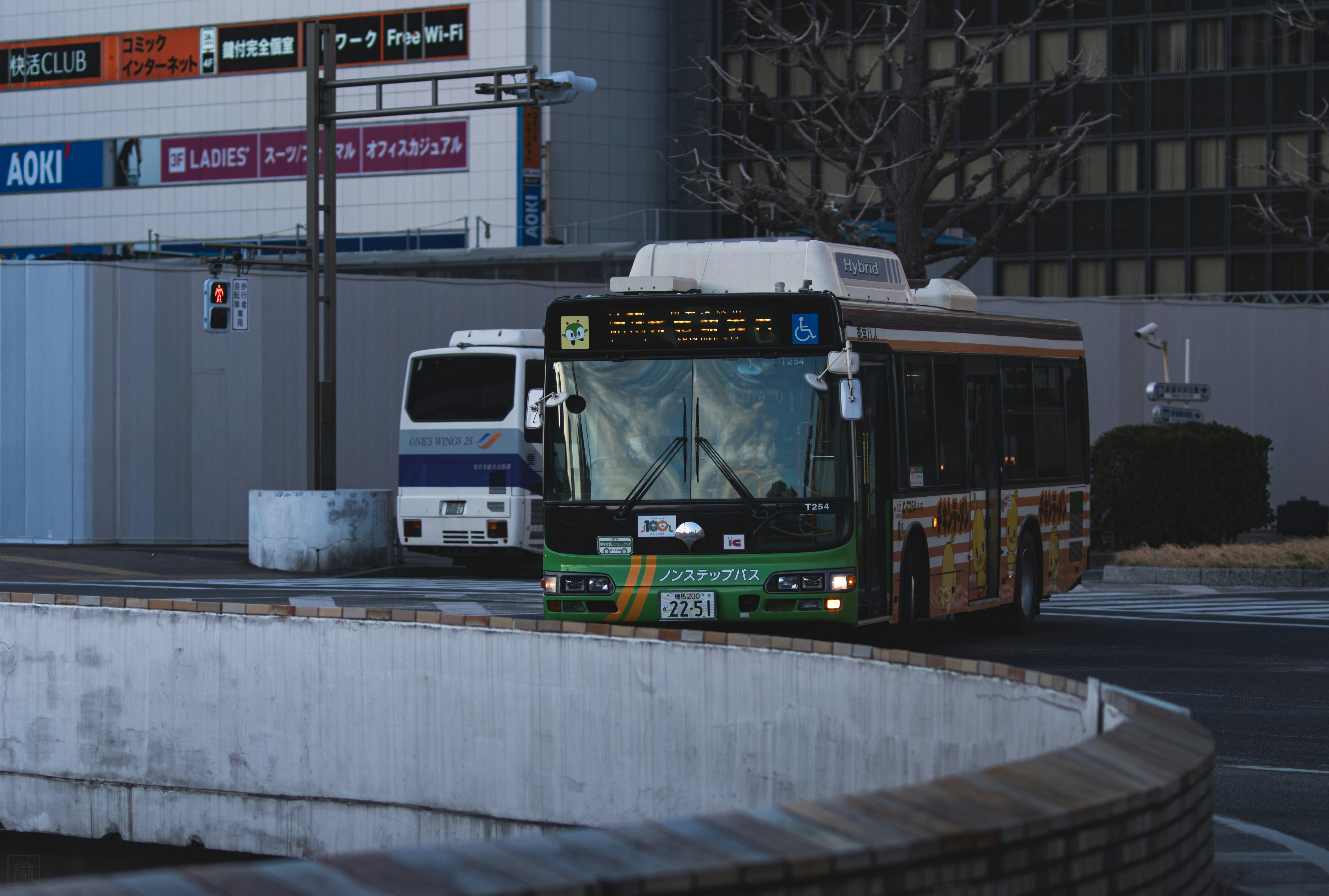 Green city bus cutting through an urban curve at dusk