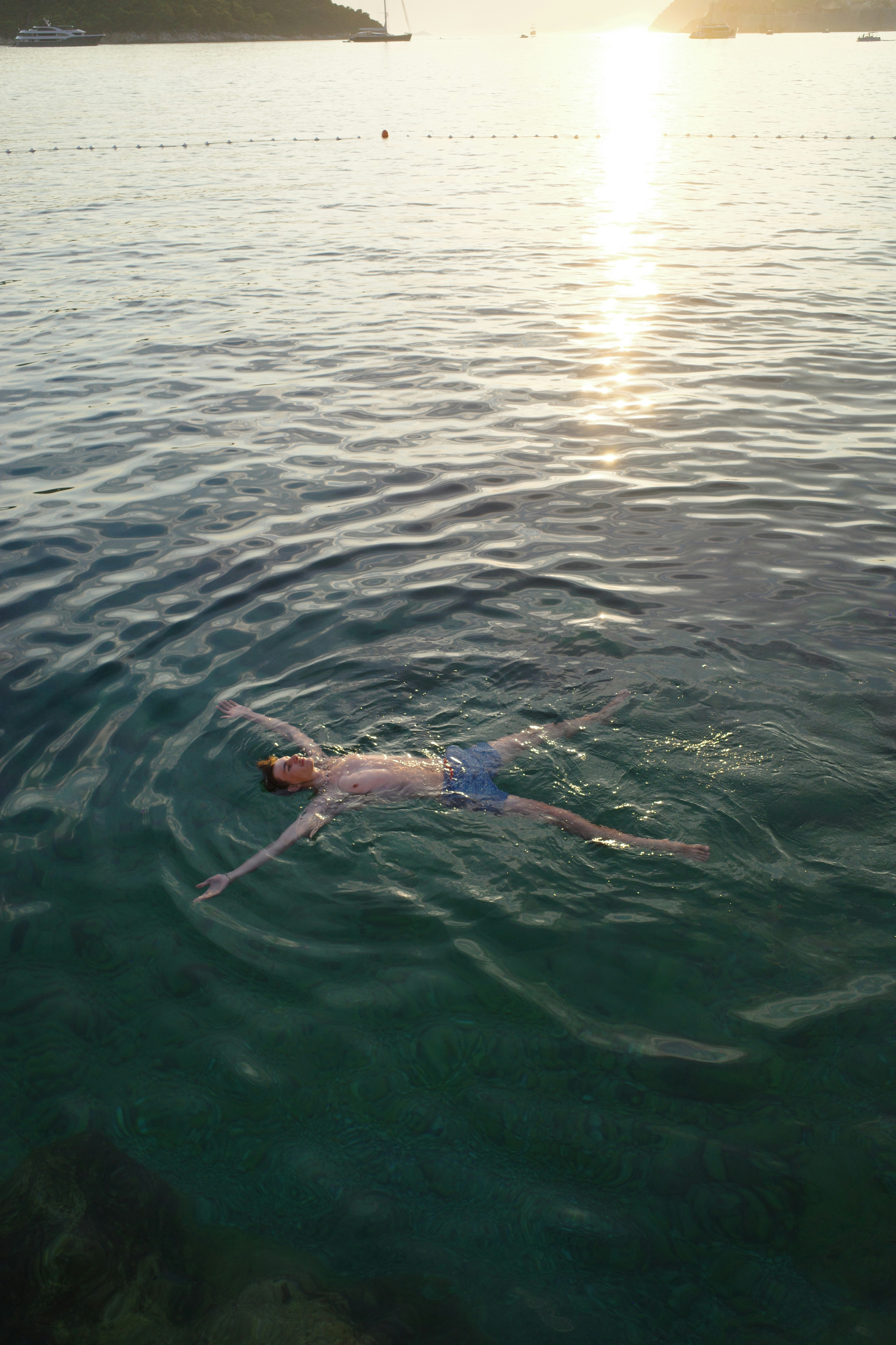 Sunlit Canvas: Swimmer Drifts in Quiet Waterfront Calm