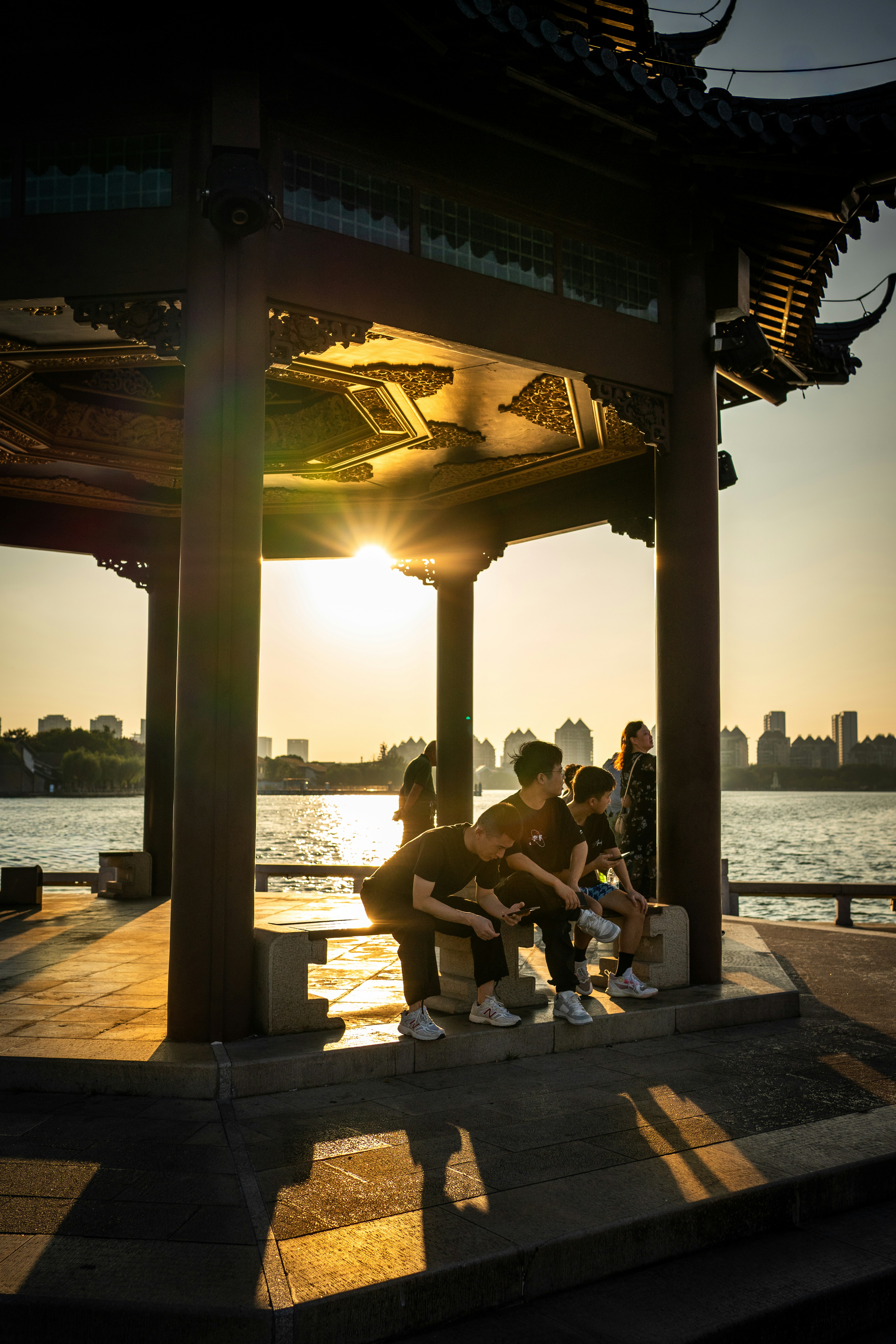 Sunlit group beneath a pavilion by the water at golden hour