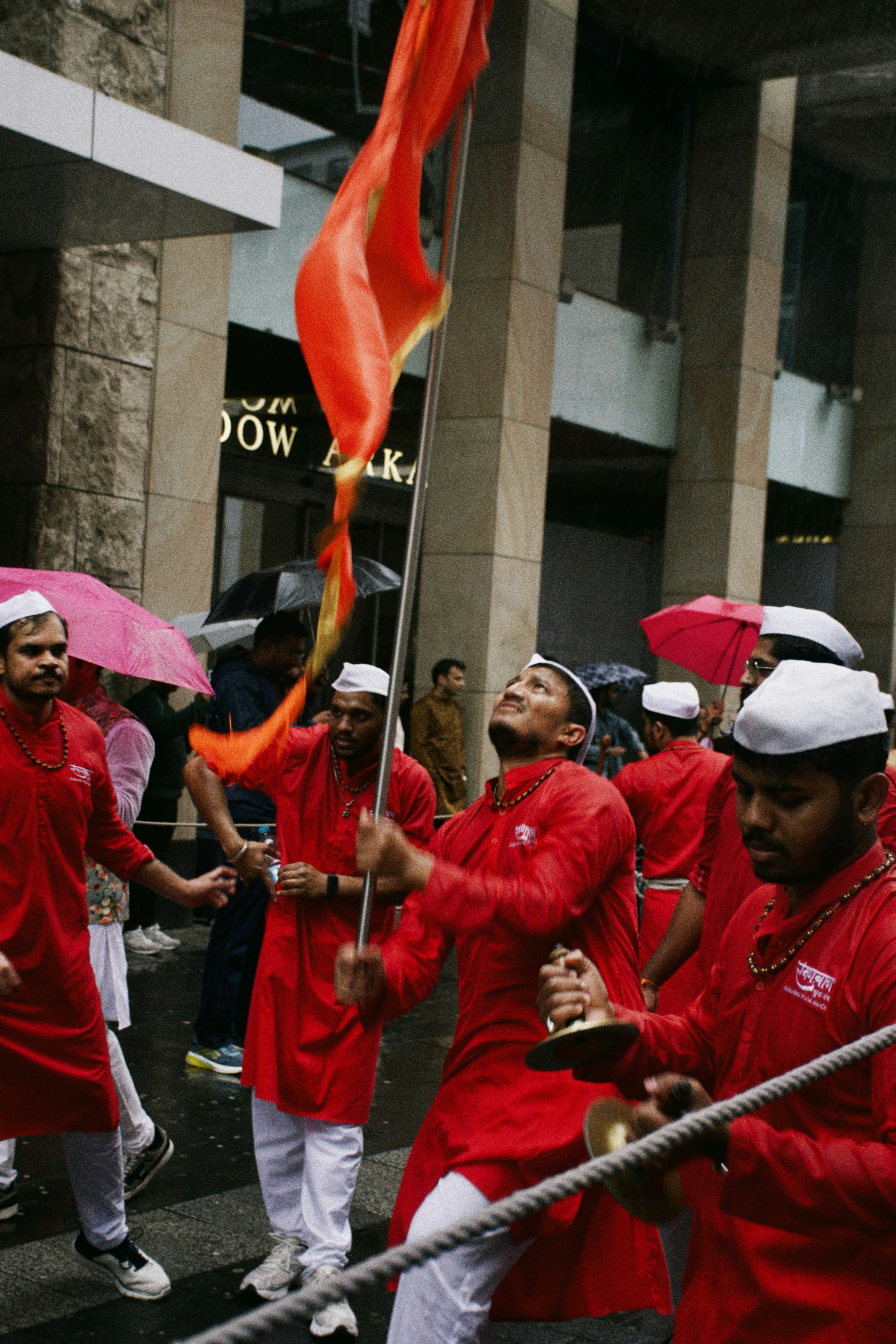 Red-clad procession under rainy city banners