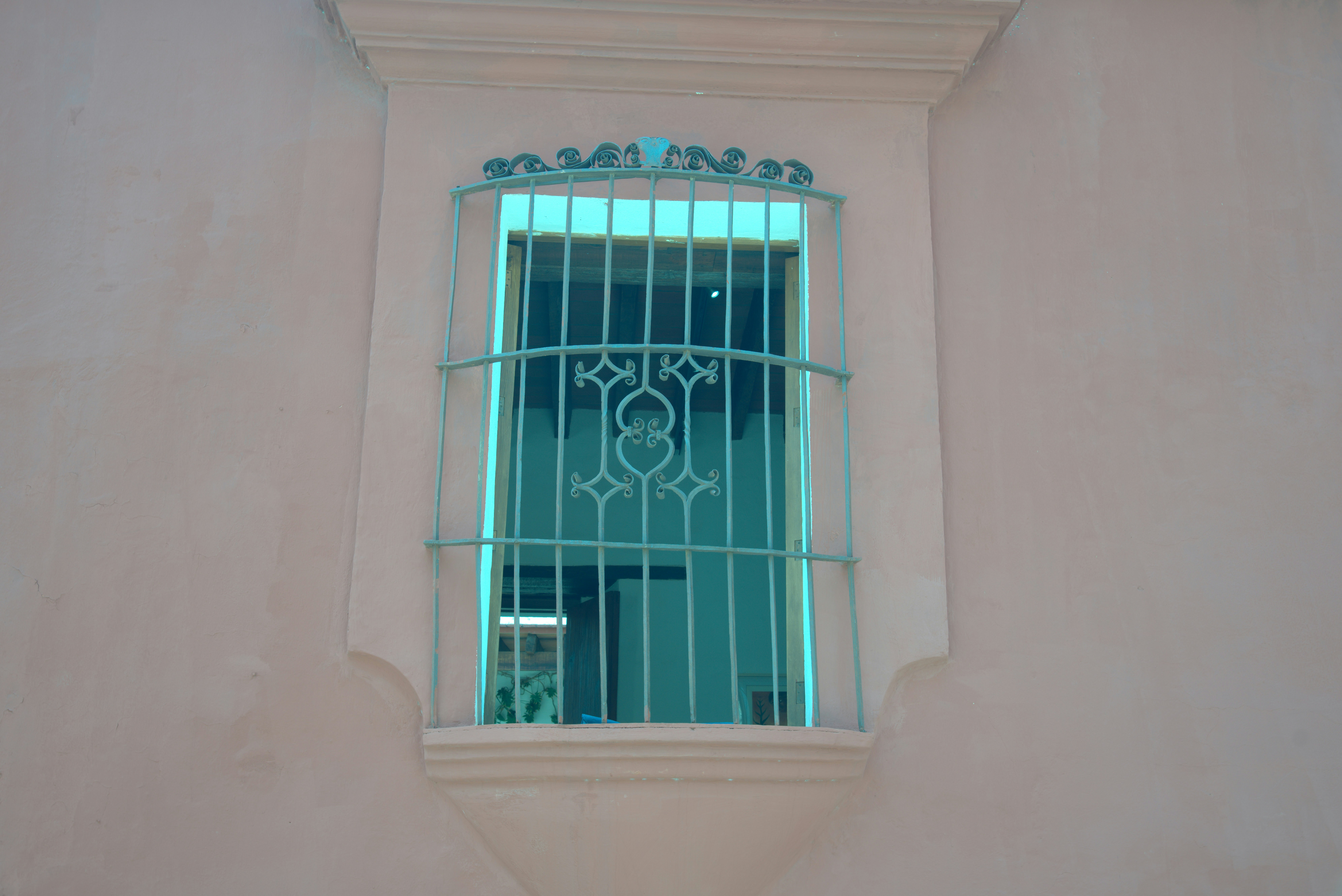 Teal-Cleared Window: A Muted House Front Framed by Architectural Grille