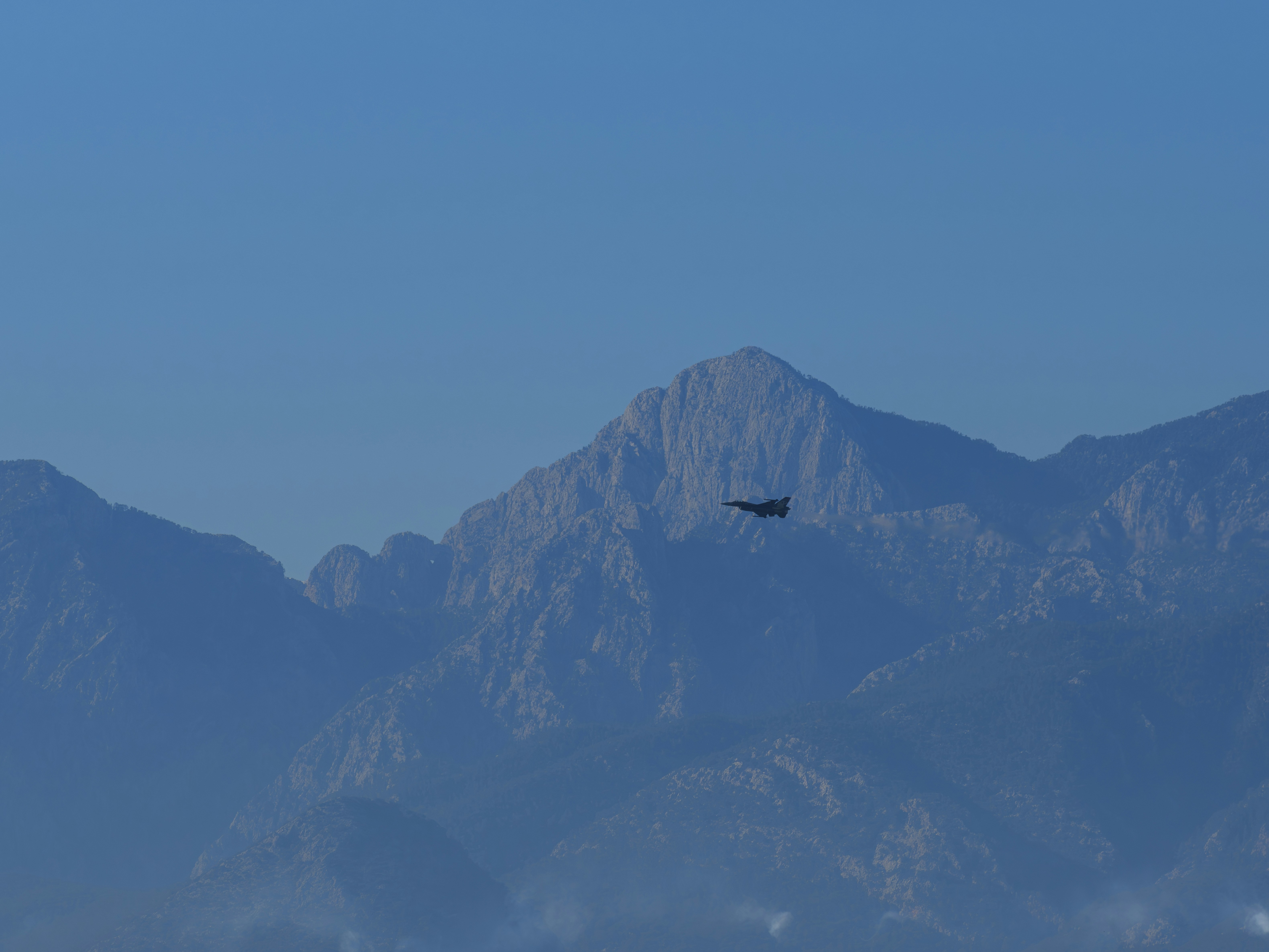 A lone helicopter over blue-tinted alpine ridges