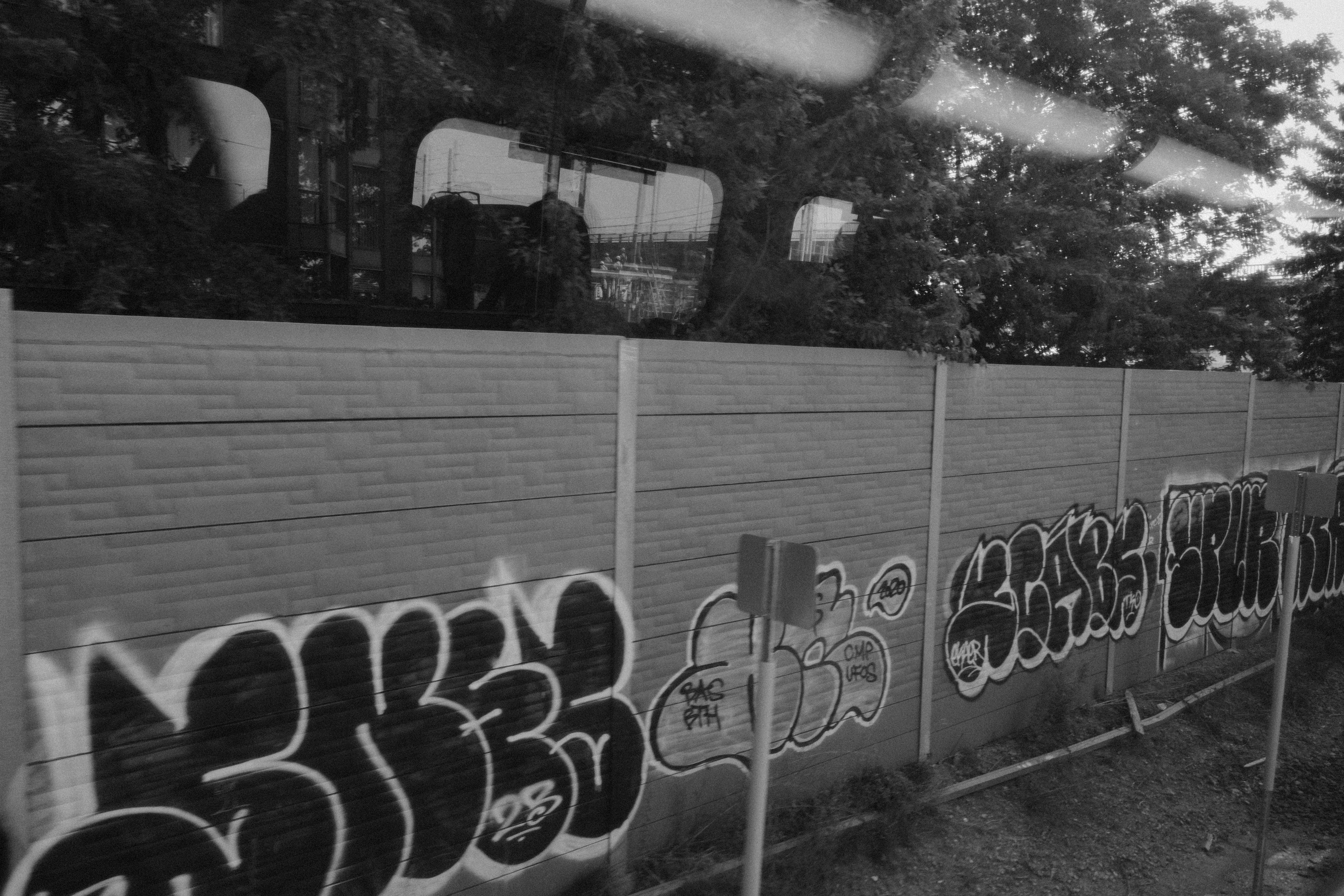 Graffiti Fence Echoes Under a Rain-Blurred Window
