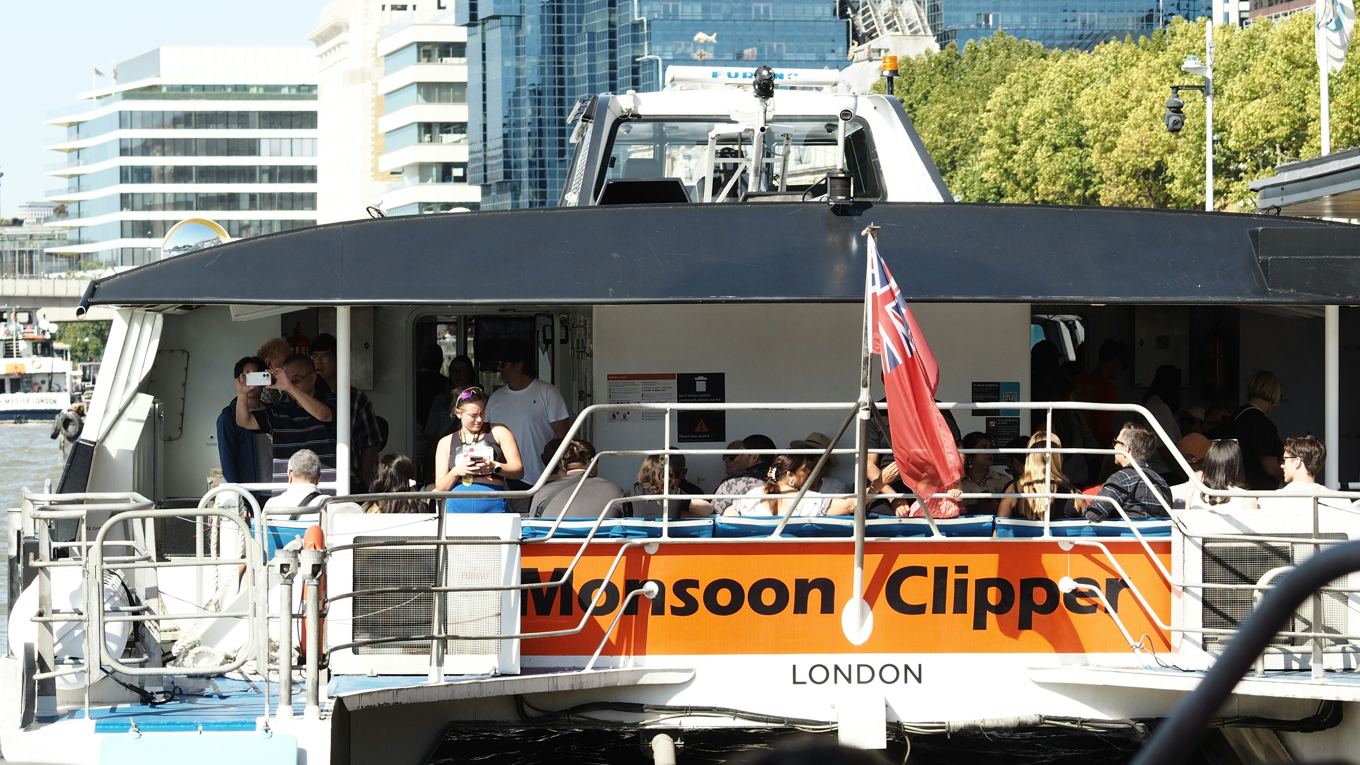 River Tour Vessel: Passengers and Orange Branding on the London–Waterside