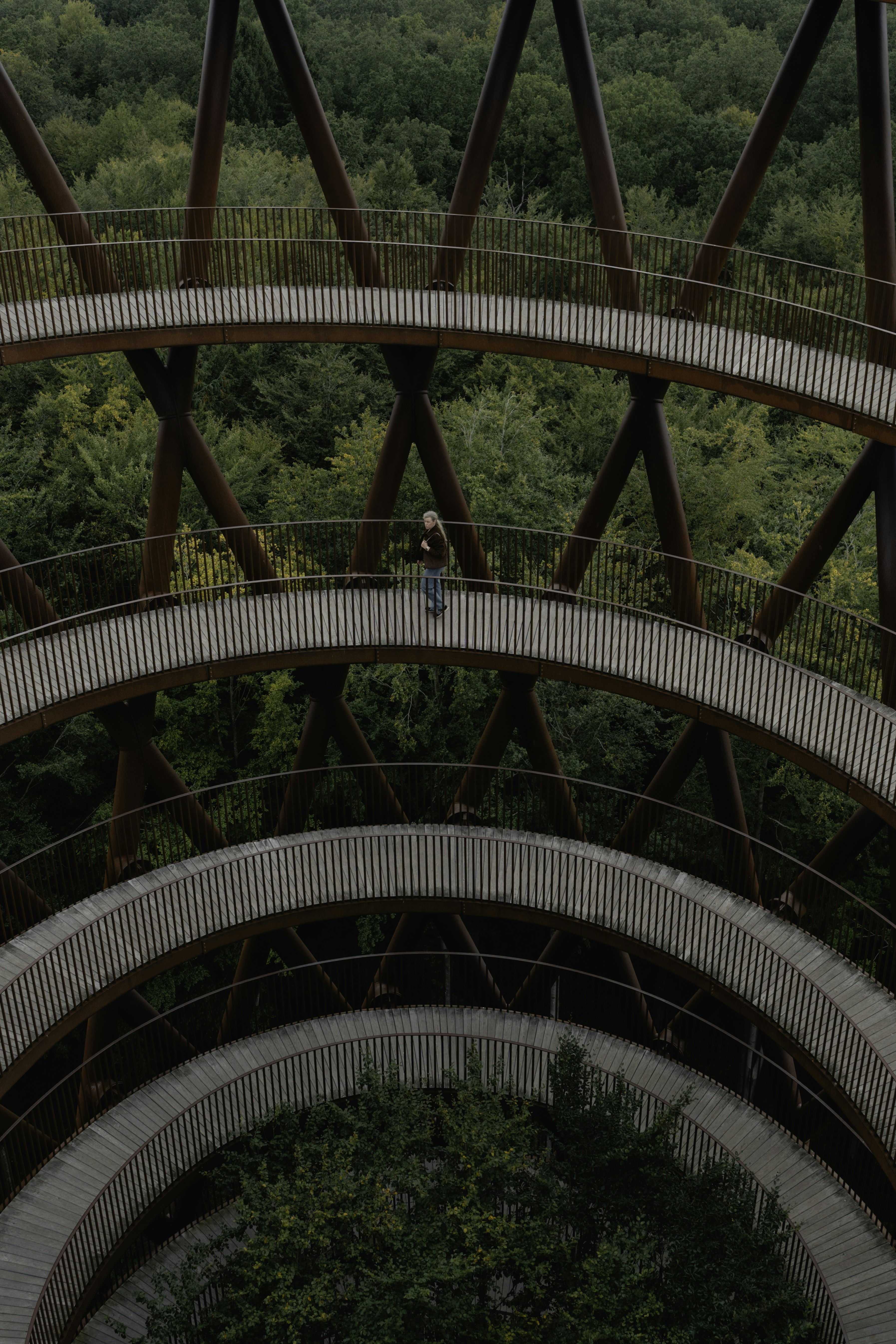 A lone walker on the inner ring of a steel spiraling bridge