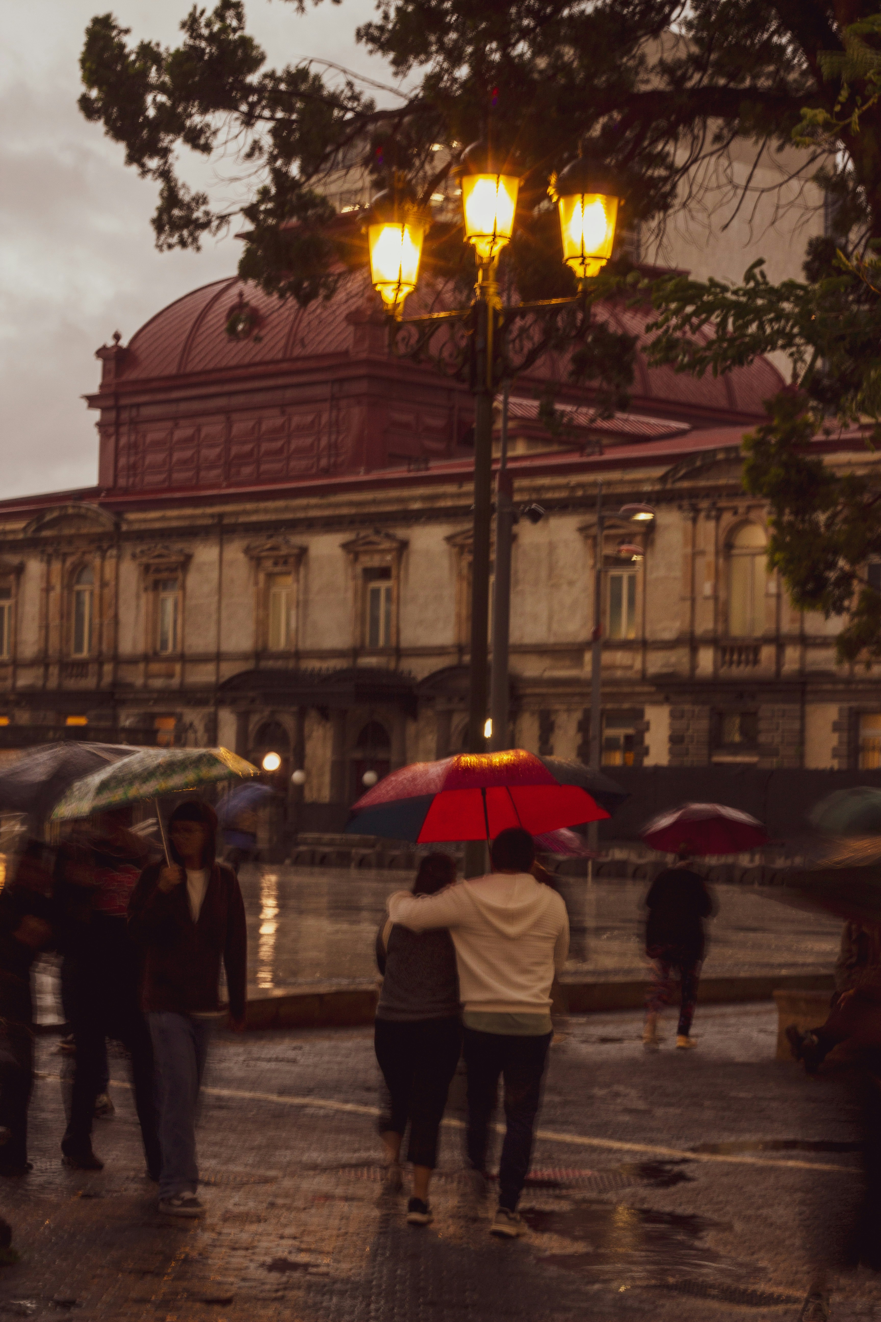 Rainy evening at the lantern-lit plaza fading into warm dusk