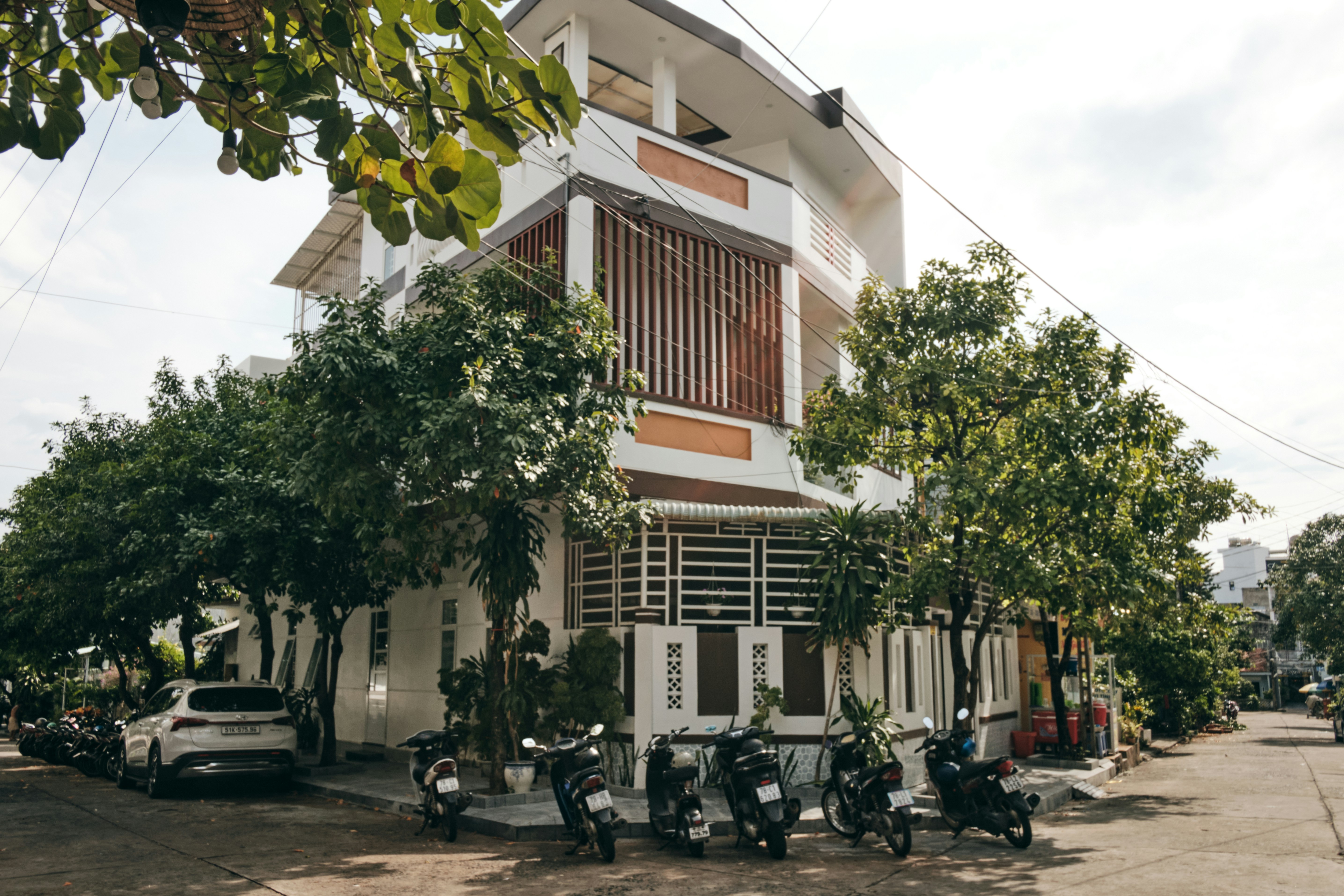 Sunny street corner with a white multi-story house framed by trees