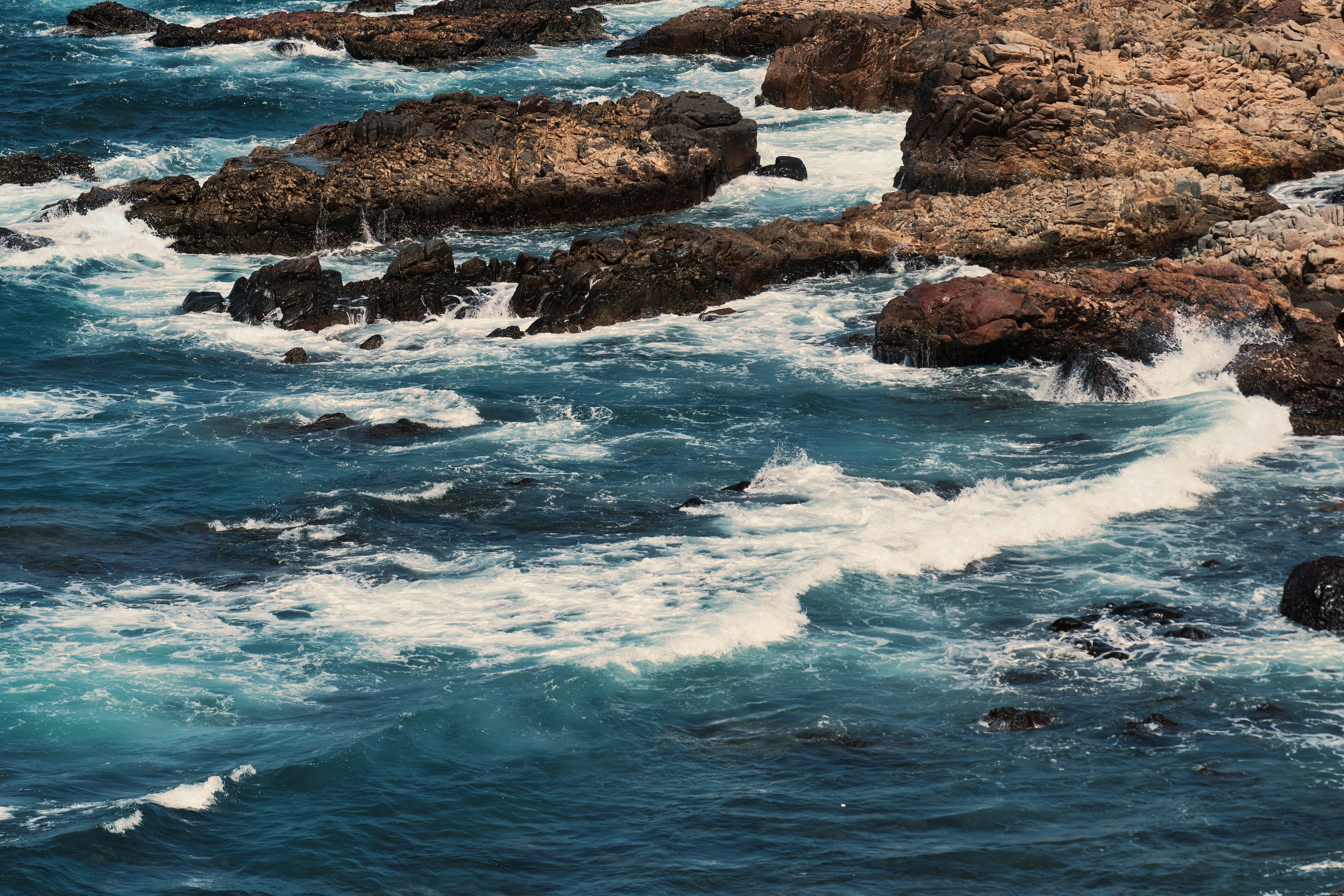 Rugged Coastline: Turquoise Surf Meeting Weathered Rocks