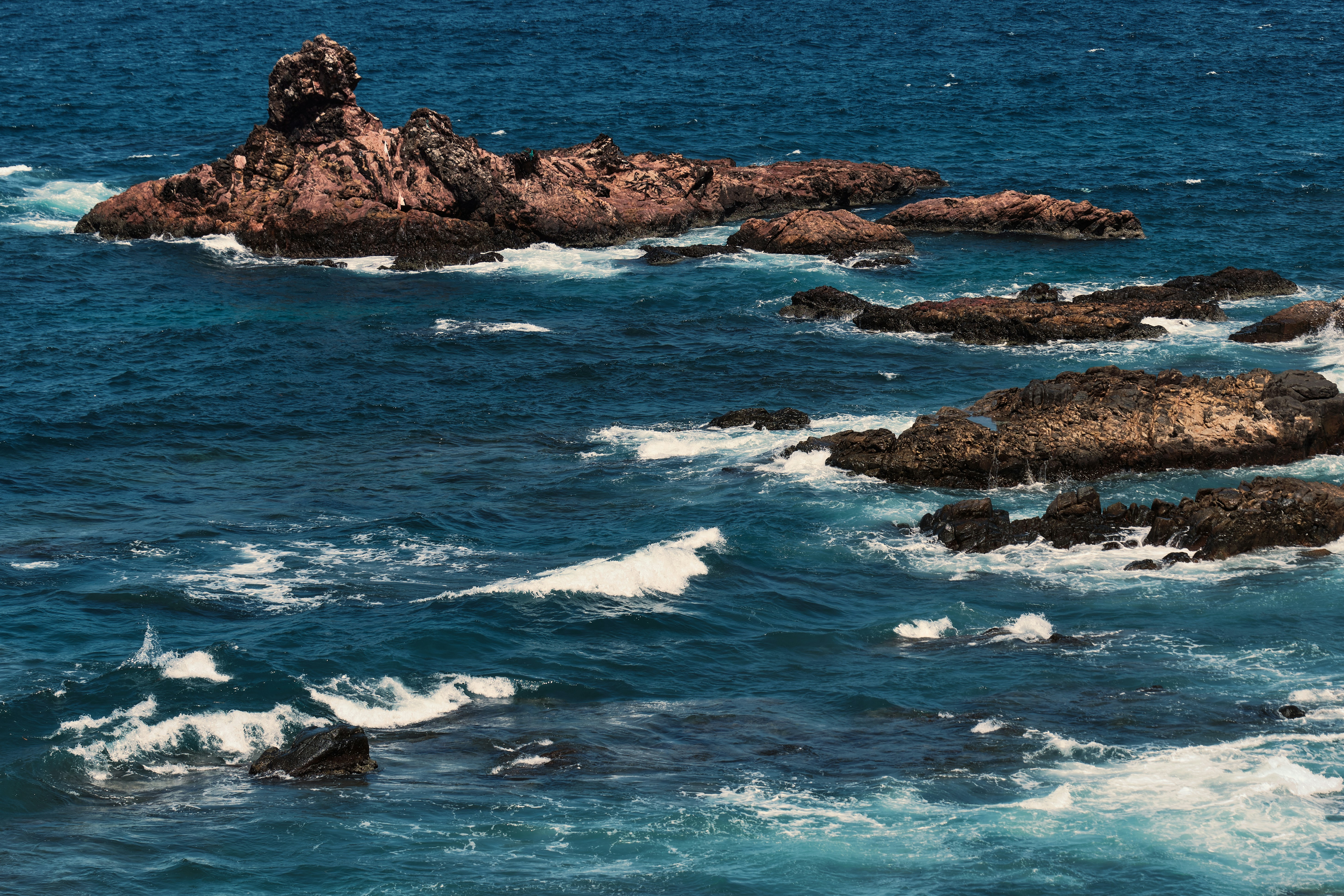 Rugged Sea Stack Emerges from the Blue: A Coastal Tease