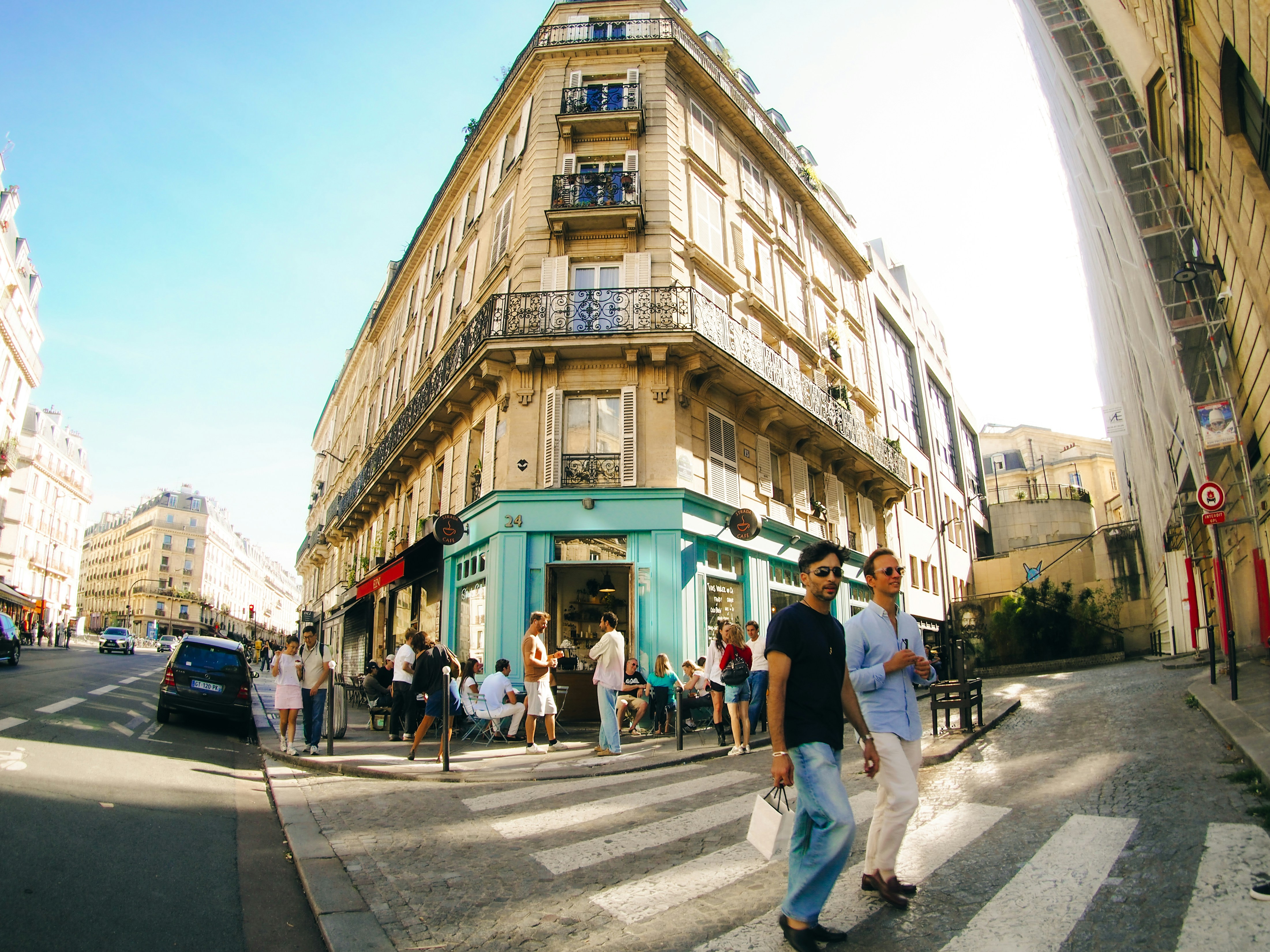 Corner Café Confluence: Sunlit Pedestrian Crossing in a Parisian Street