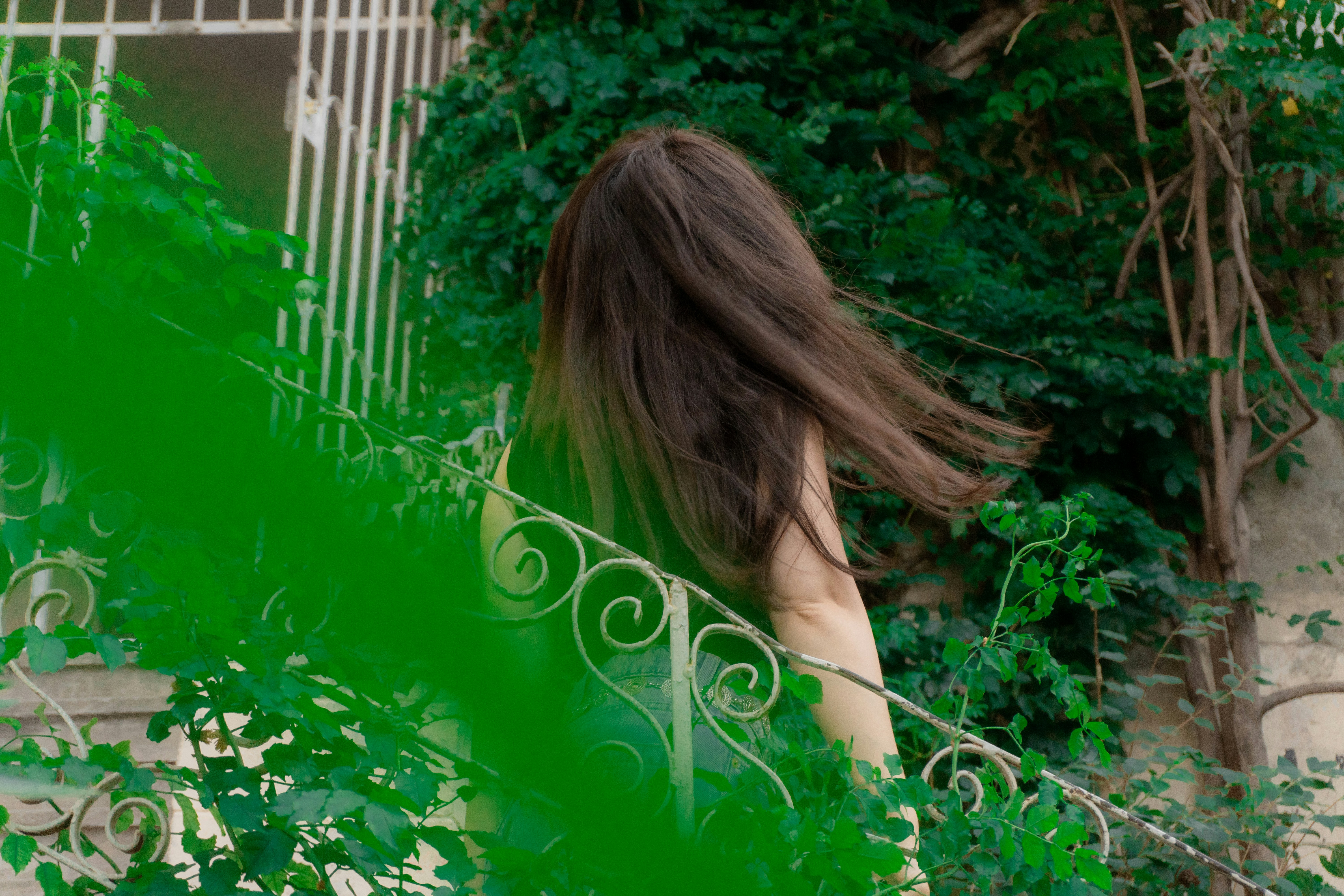 Whispering Veil: A Figure Behind Verdant Scrolls