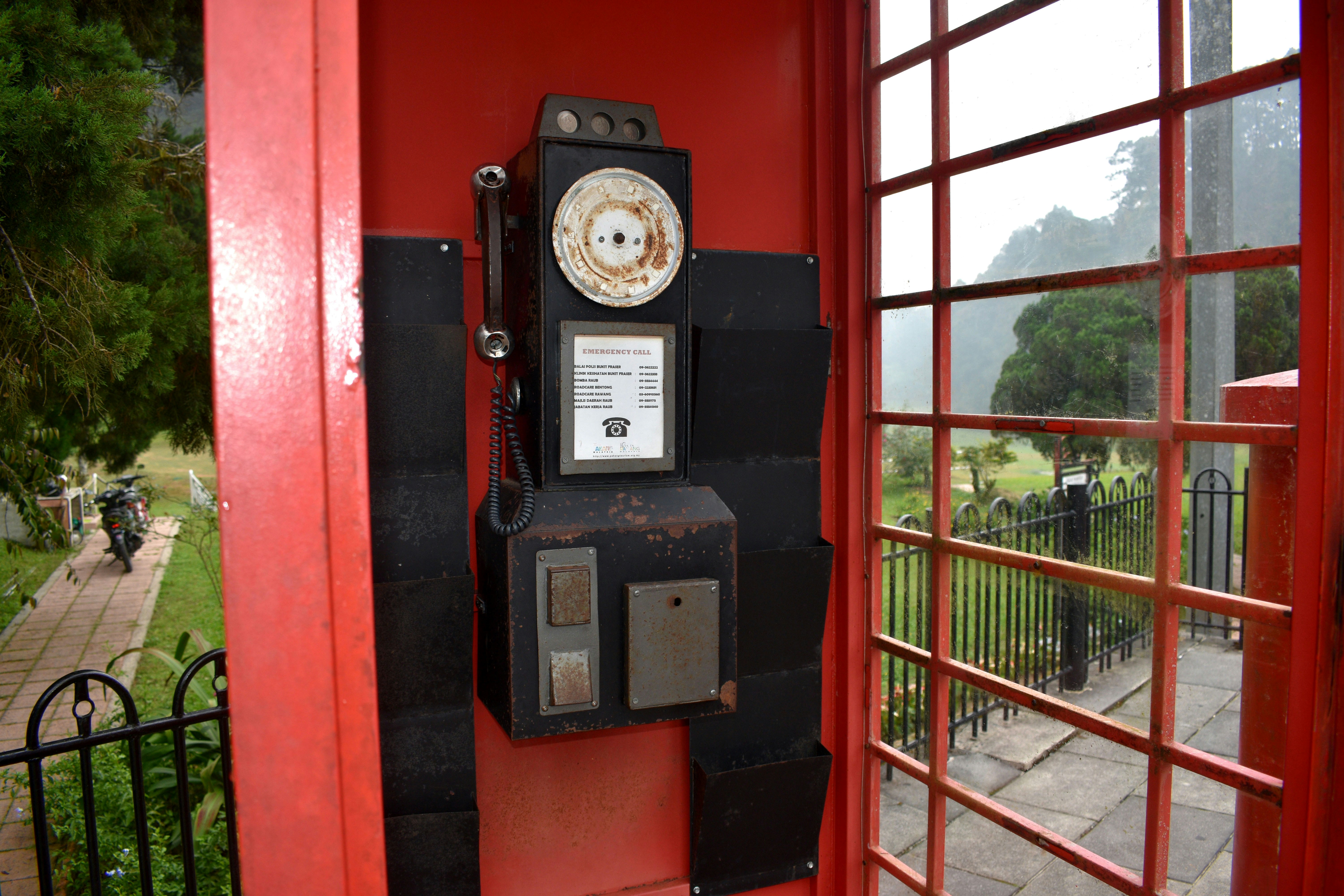 Corrugated Silence: An Old Payphone Within a Red Kiosk Frame