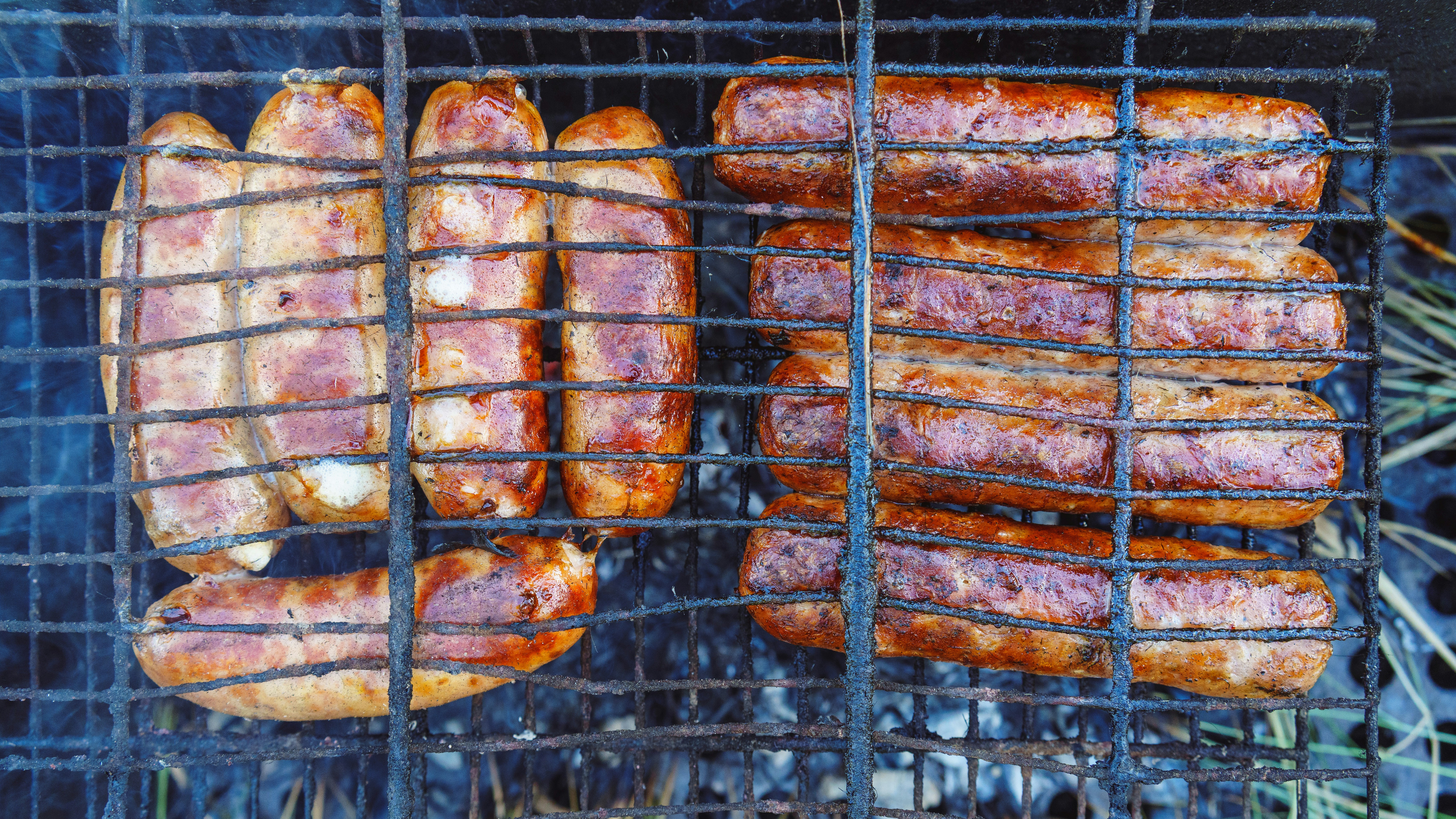Grilled sausages cooking on a metal grate over a charcoal fire