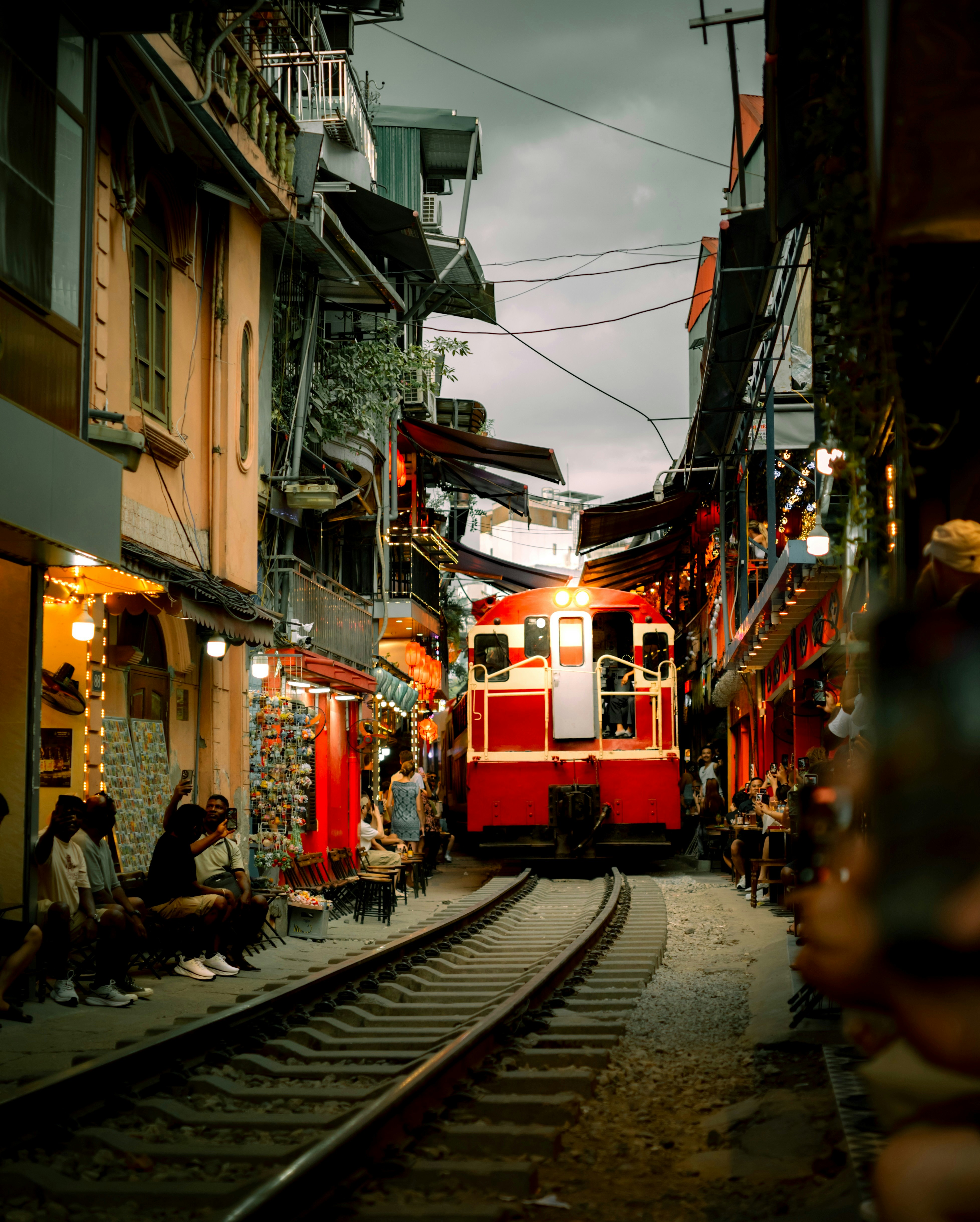 Red Locomotive in a Lantern-Lit Alley: Train Tracks Through a Night Market