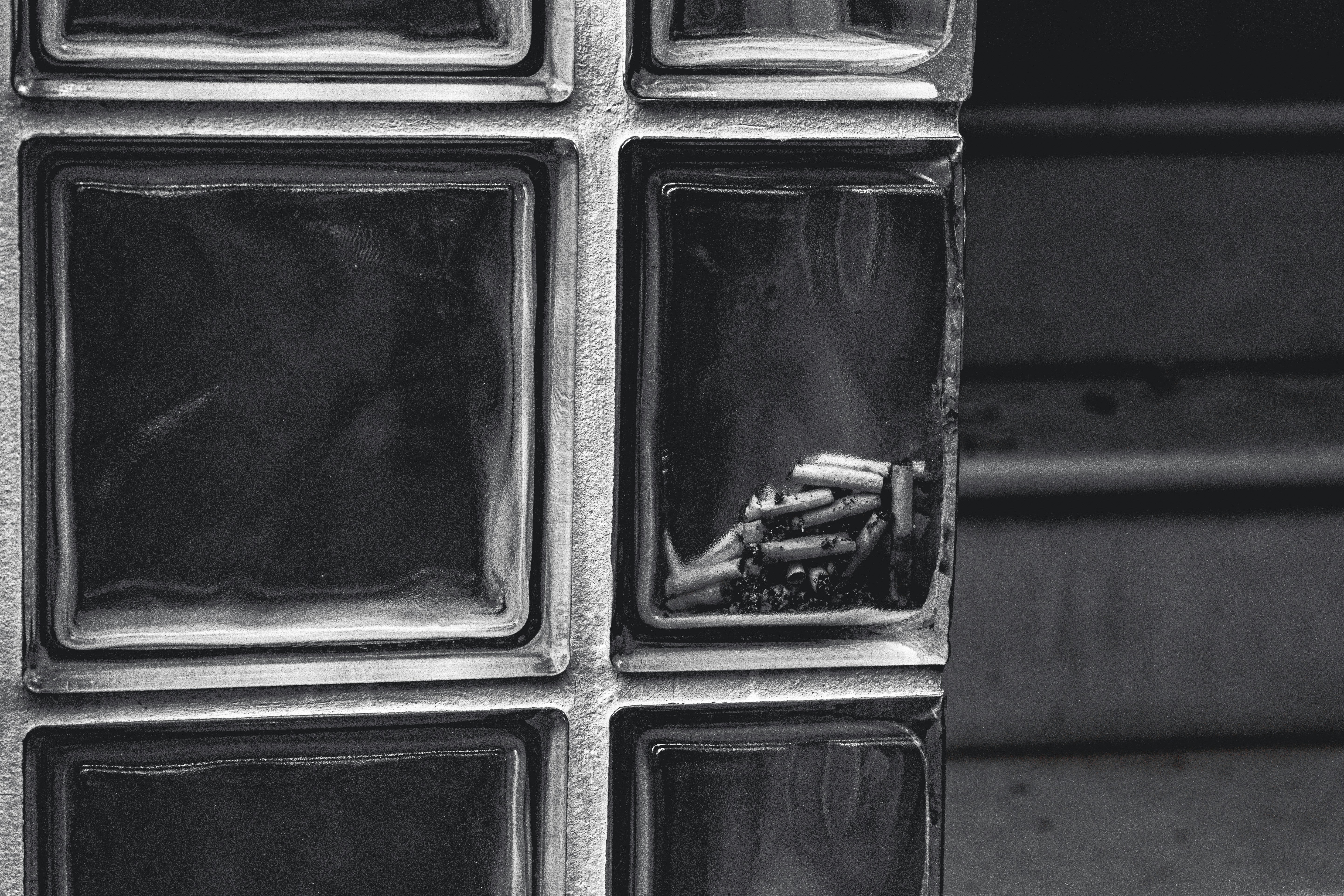Close-up of a lit cigarette resting next to an ashtray on a frosted glass table