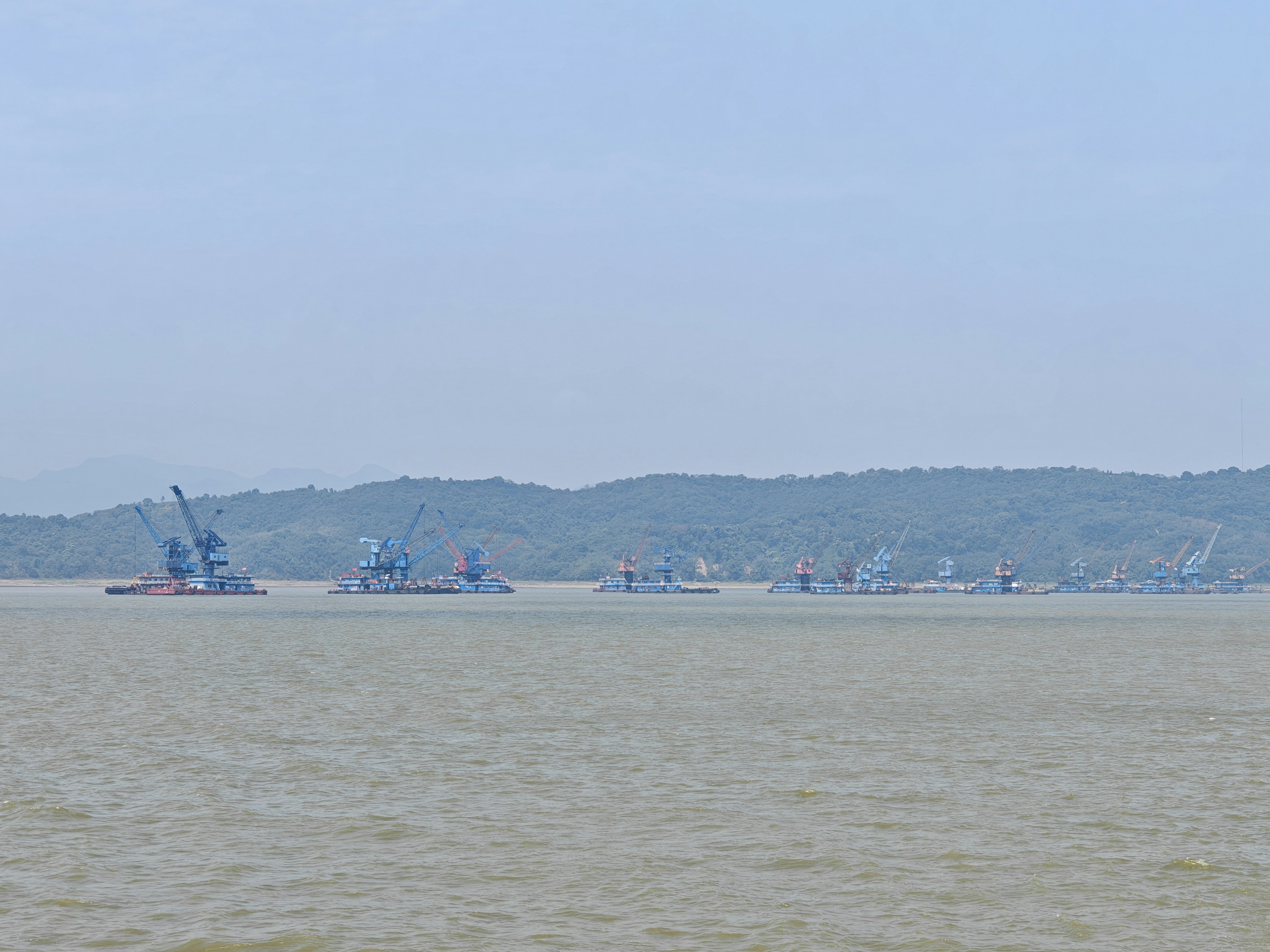 Harbor Silhouettes: Cranes Mirroring a Distant Shore