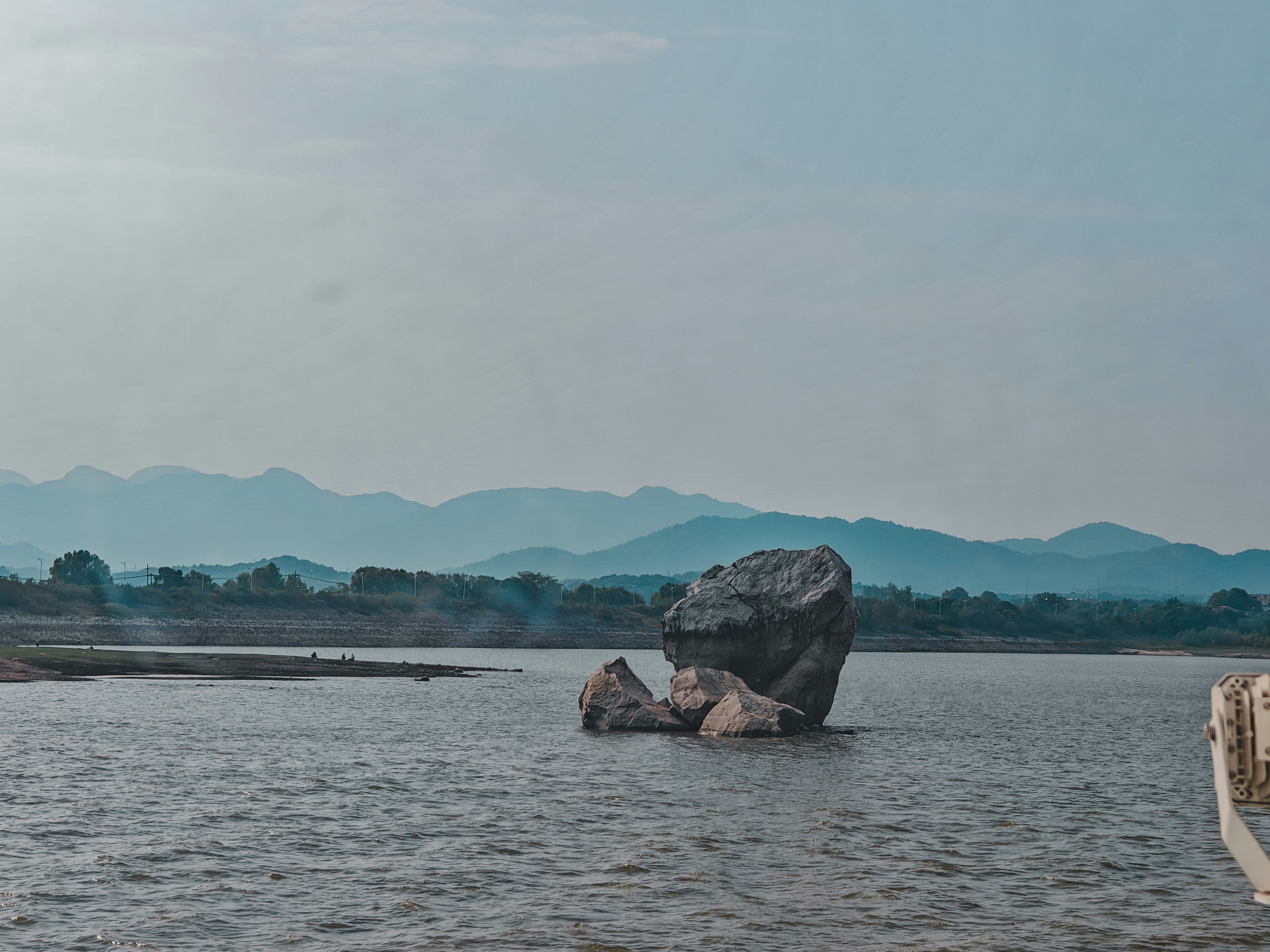 Rock Sentinel: A lone boulder steadies the river against distant hills