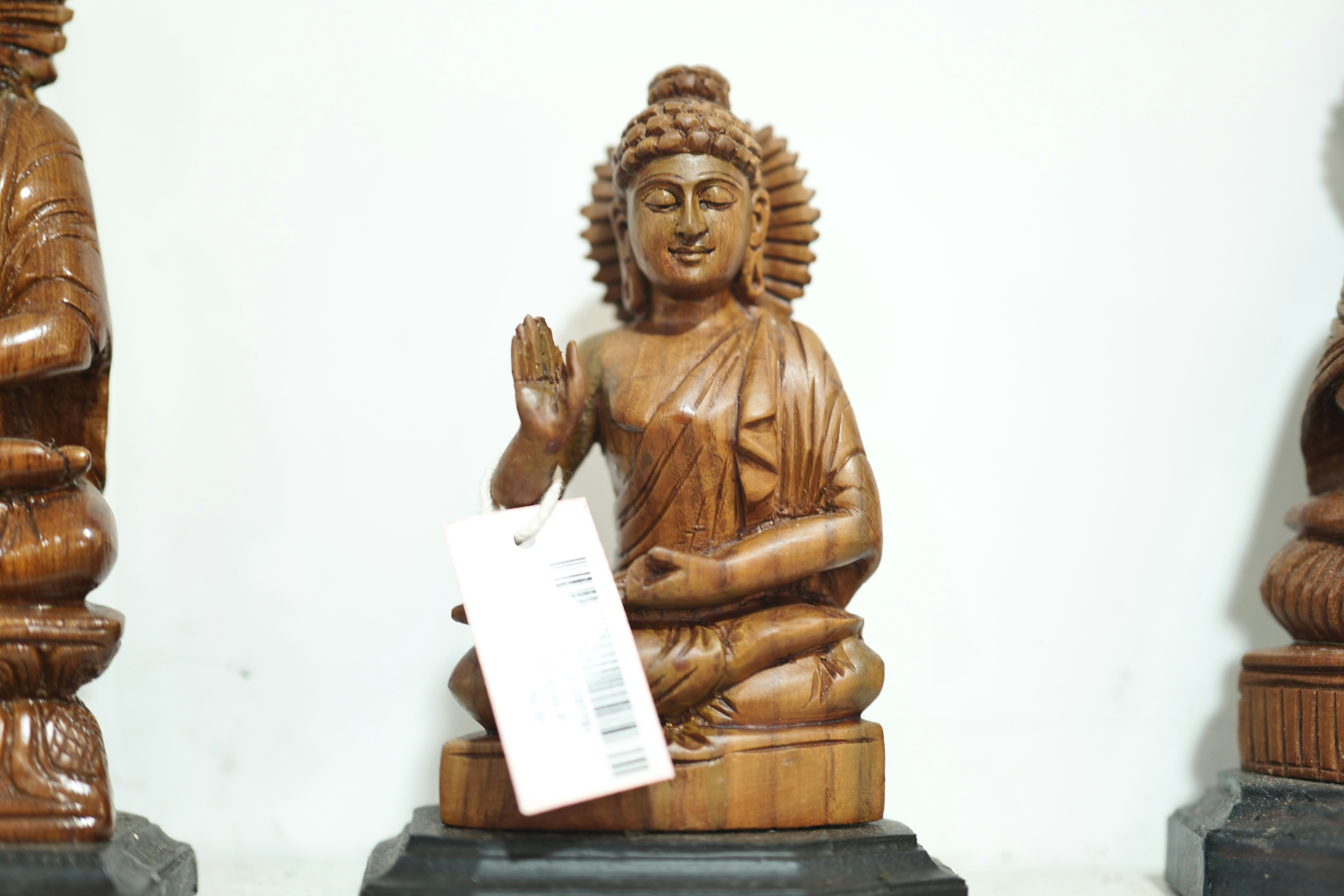 Centered Buddha: calm wooden figure with tag in a quiet gallery