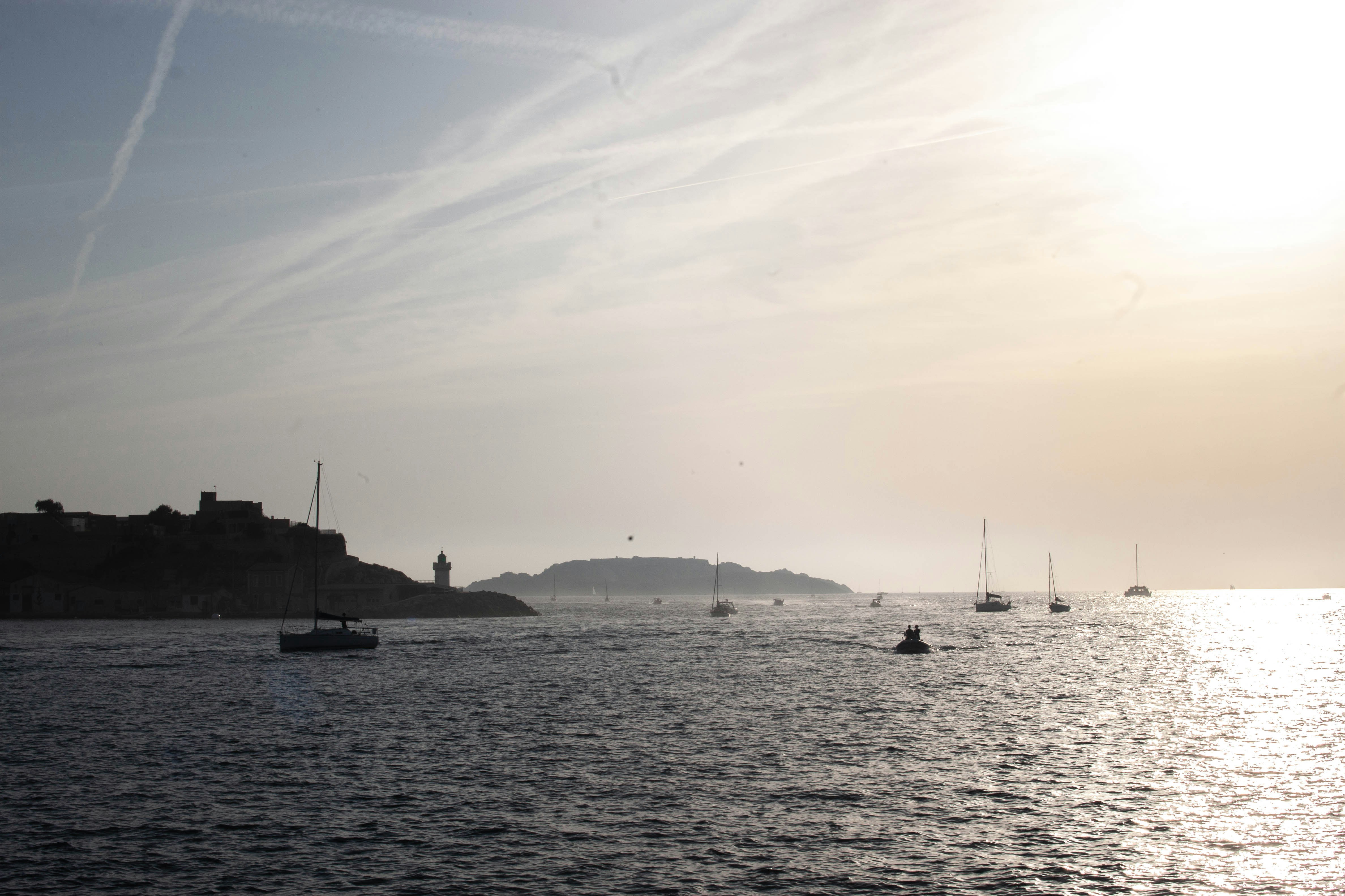 Sunlit Harbor: Boats Skimming a Calm Corridor