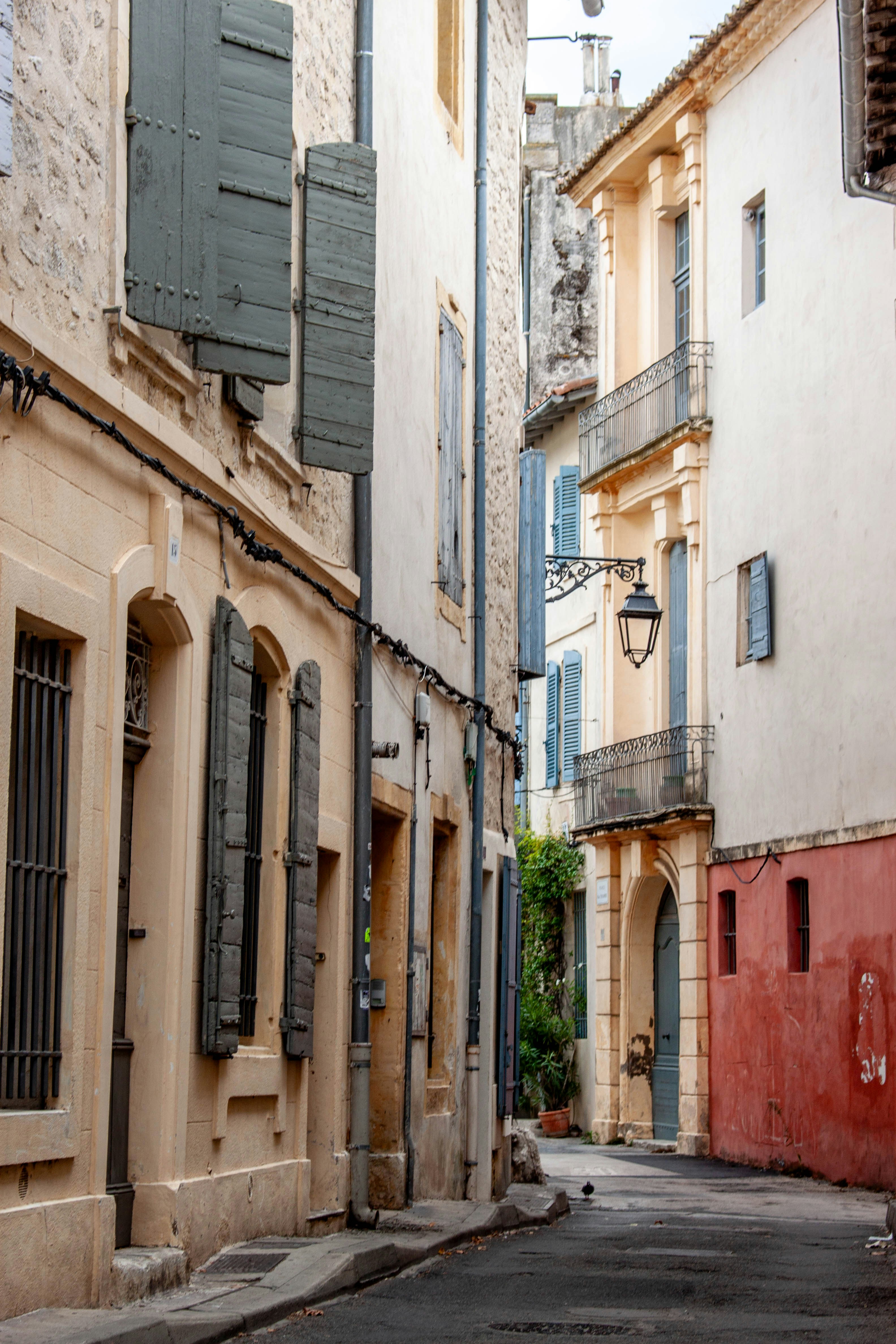 Sunlit Calle in Warm-Toned Town: Shutters, Archways, and a Quiet Path