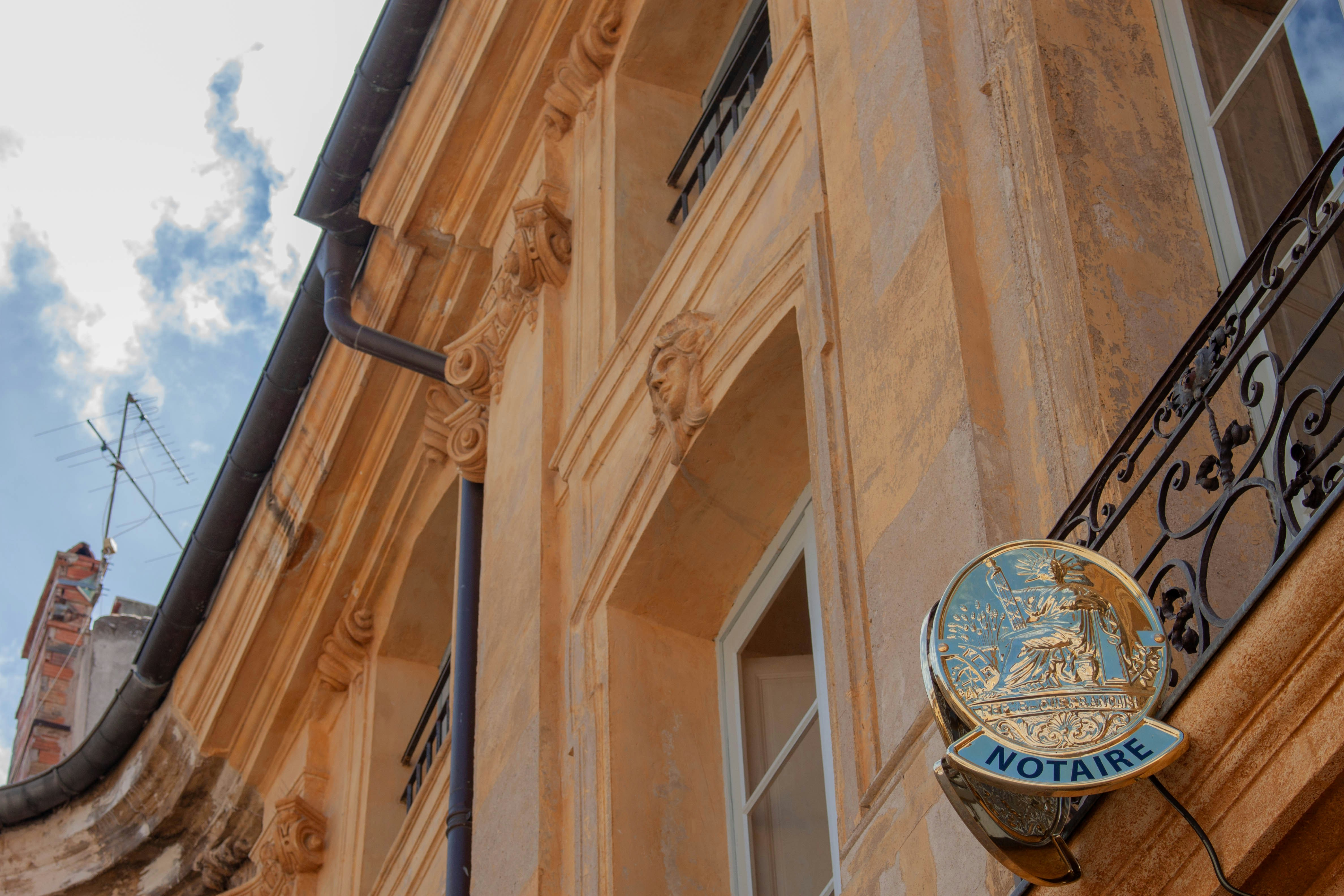 Notaire’s Emblem: Sunlit Facade and Ornate Balcony