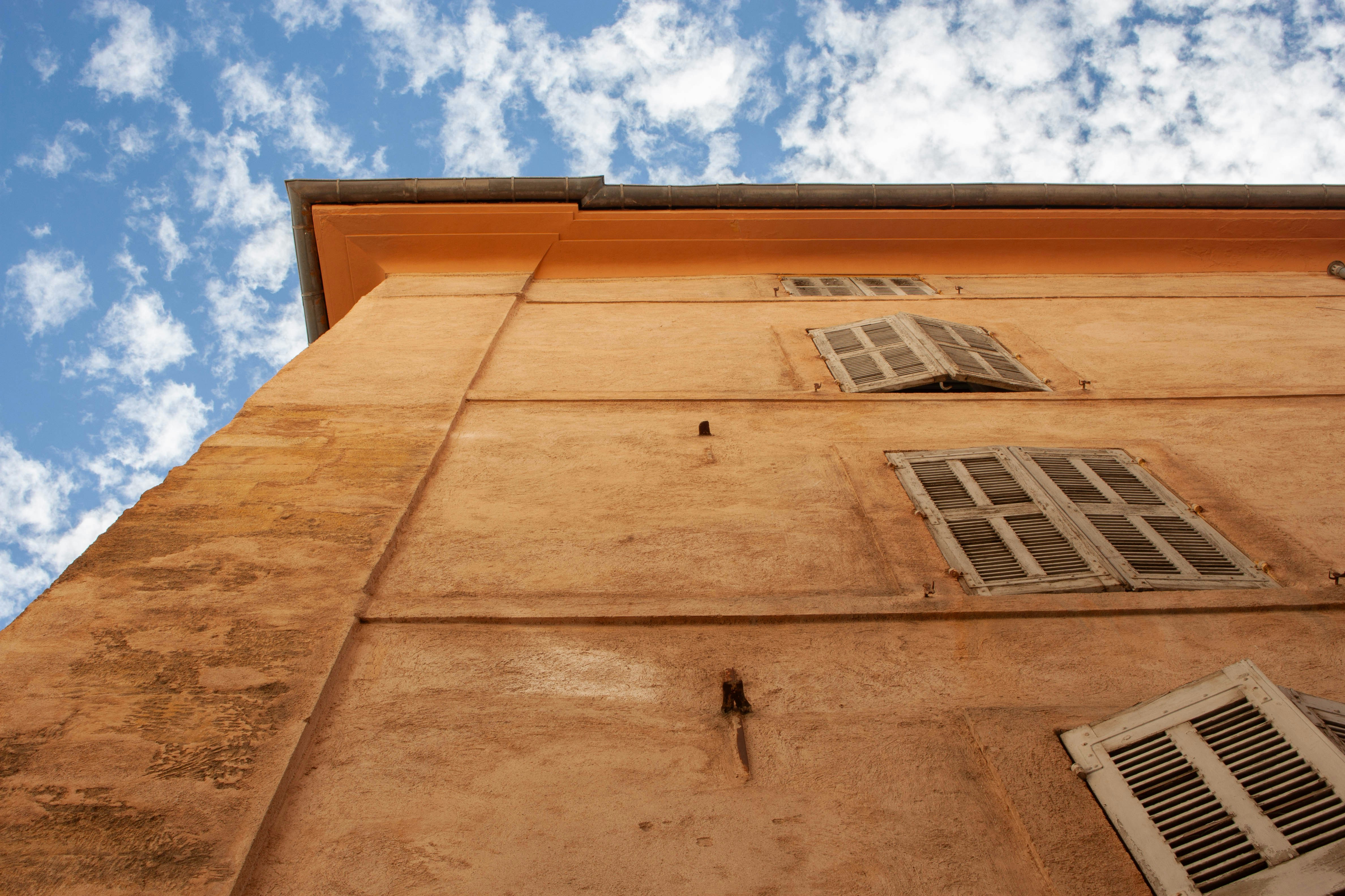 Sunlit Facade Tilt: An Aged Wall Reaching for the Sky