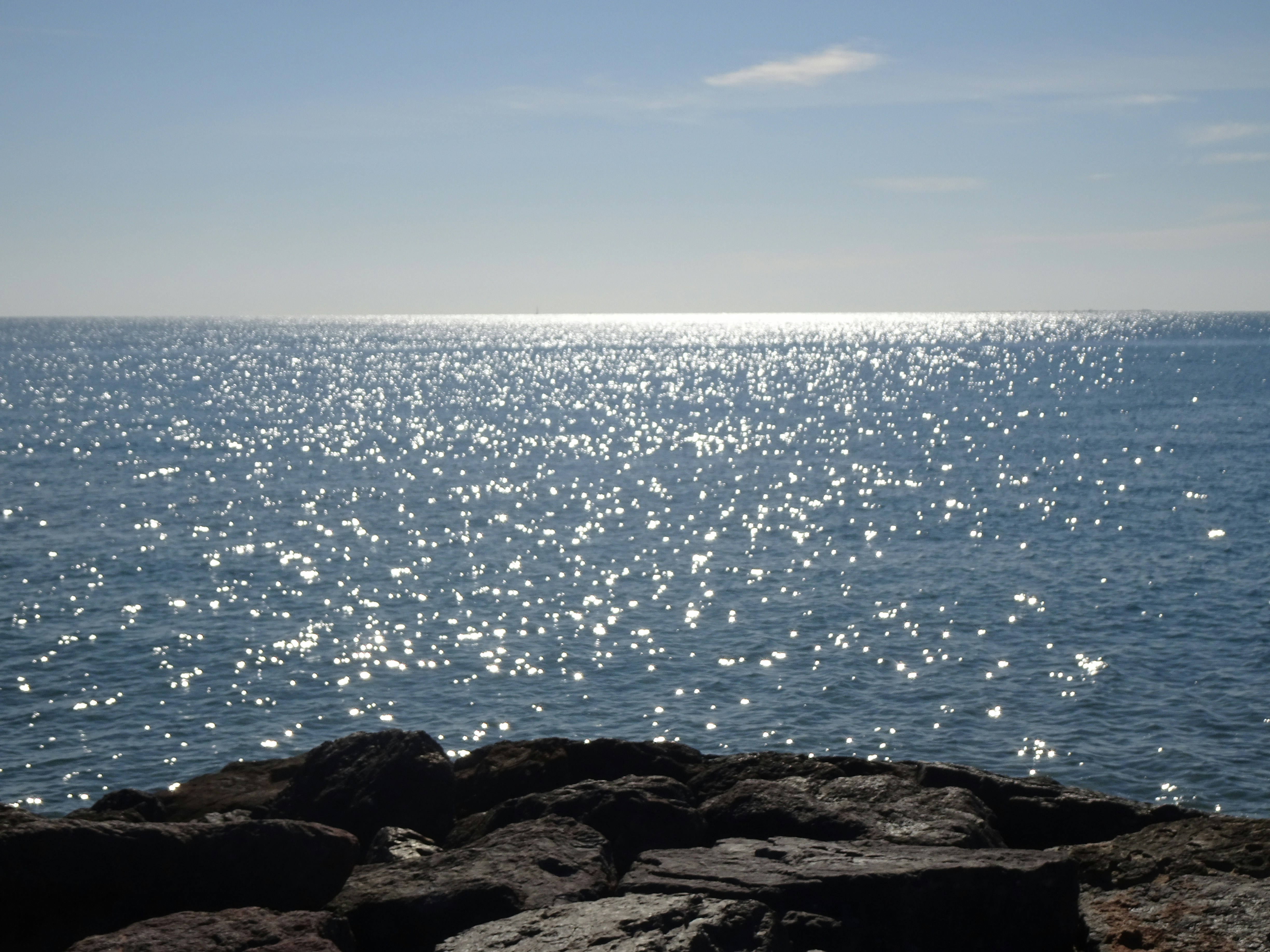 Glittering Horizon: Sunlit Sea from the Rocky Shore