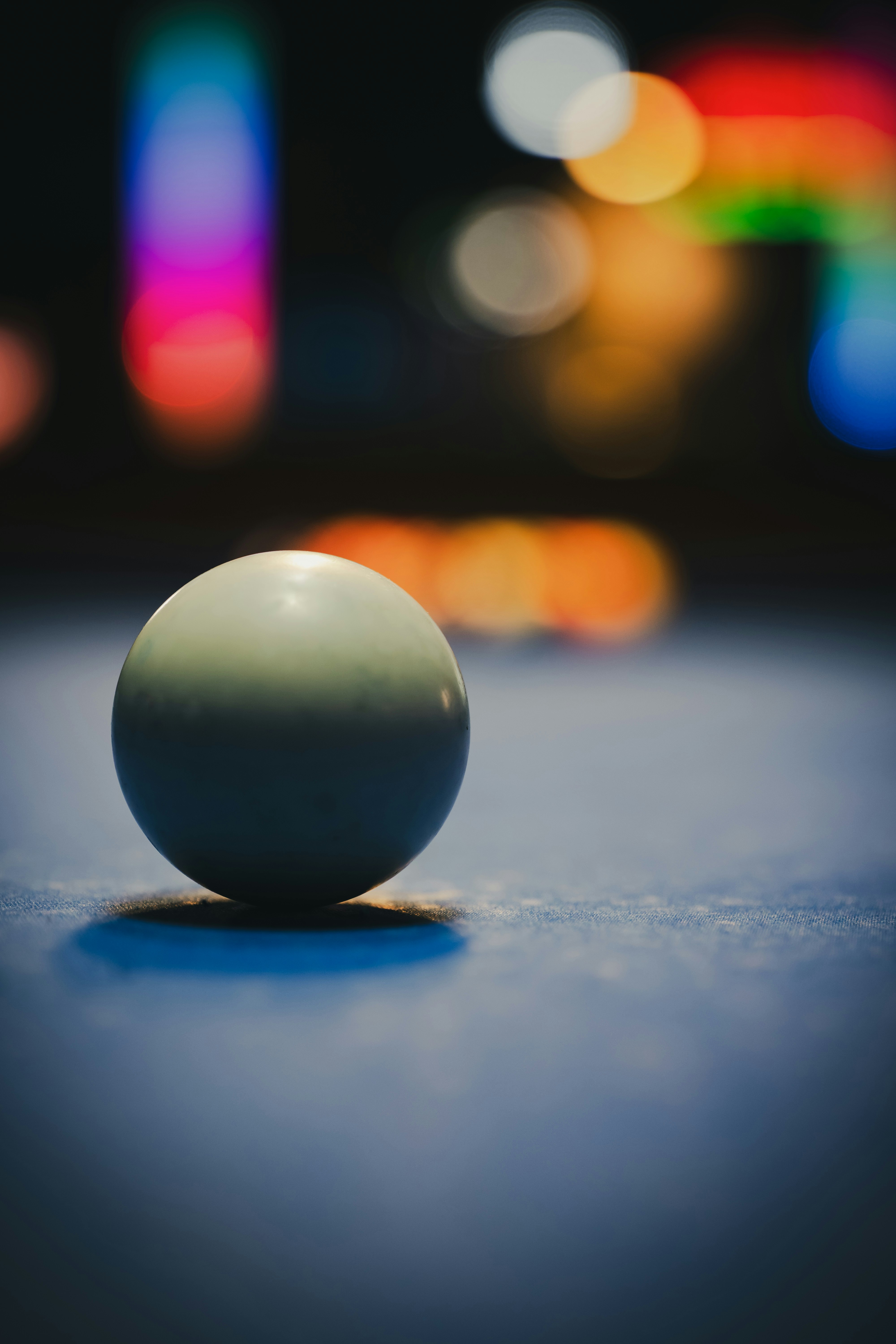 Single billiard ball in sharp focus before a neon-night backdrop