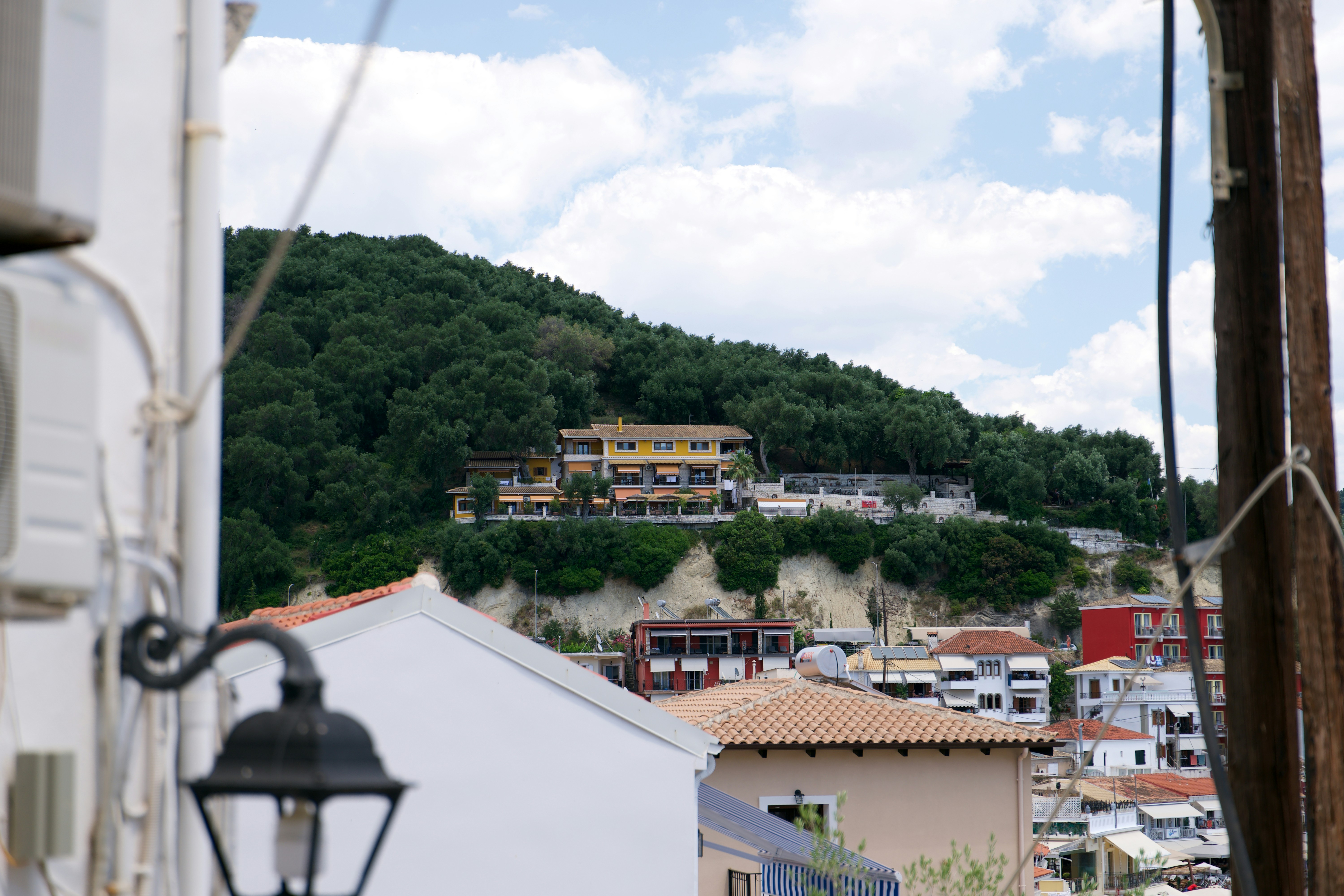  hillside village nestling under a green ridge, framed by foreground utility poles