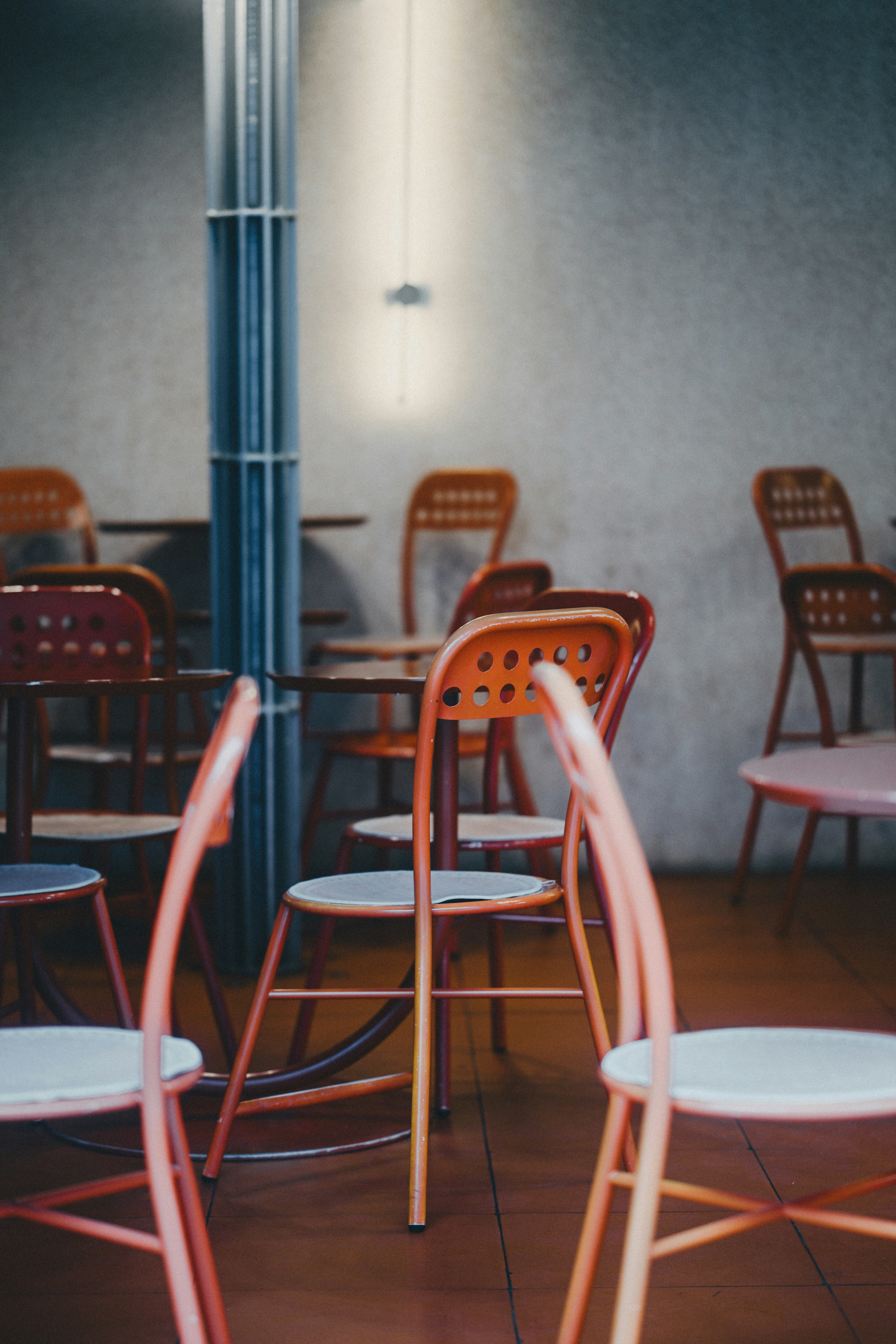 Central Orange Chair Framed by a Quiet Cafe of Curved Stools