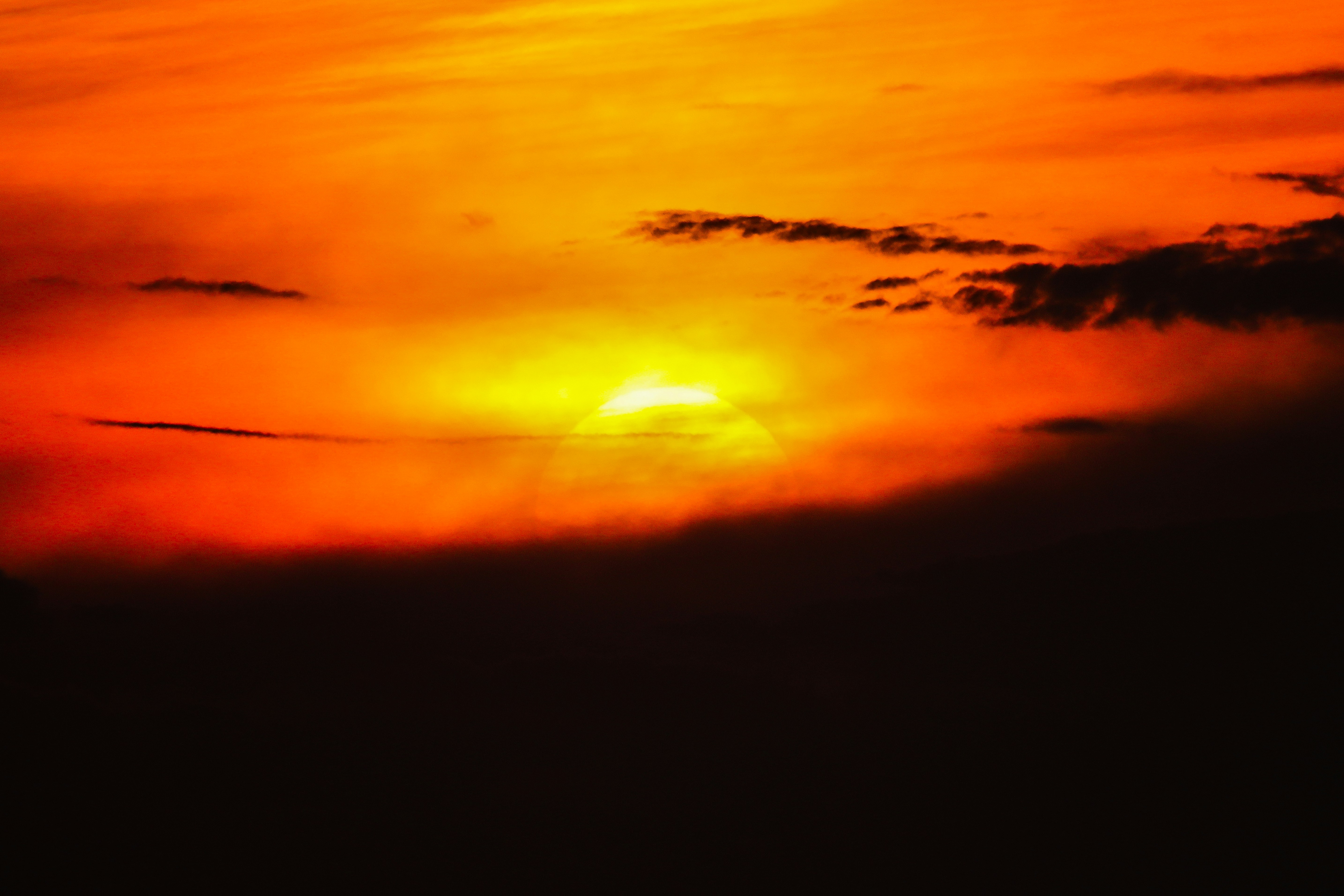 Sunset on the Horizon: Fiery Clouds over a Darkened Plain