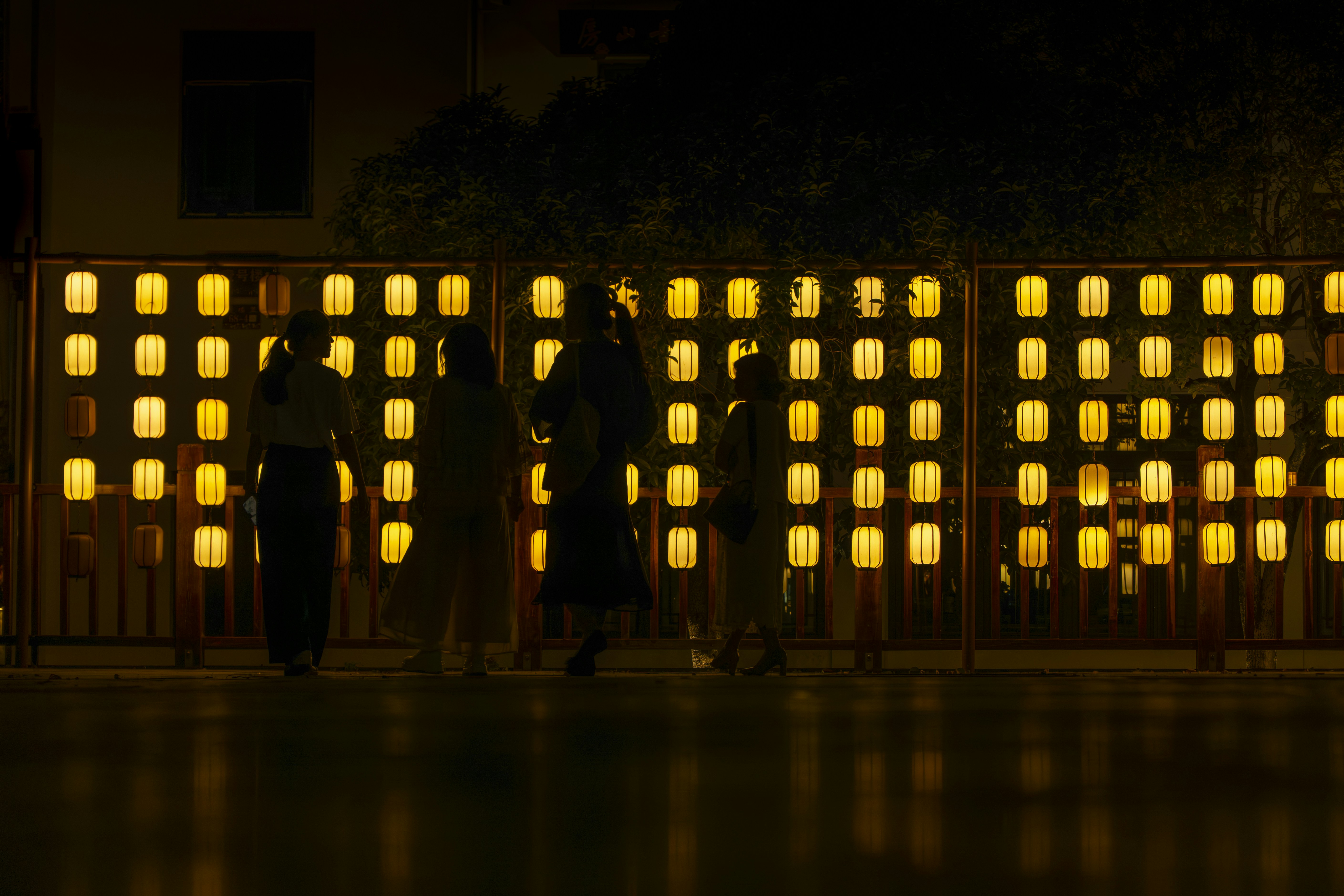Lantern-lit silhouettes by the row of glowing orbs