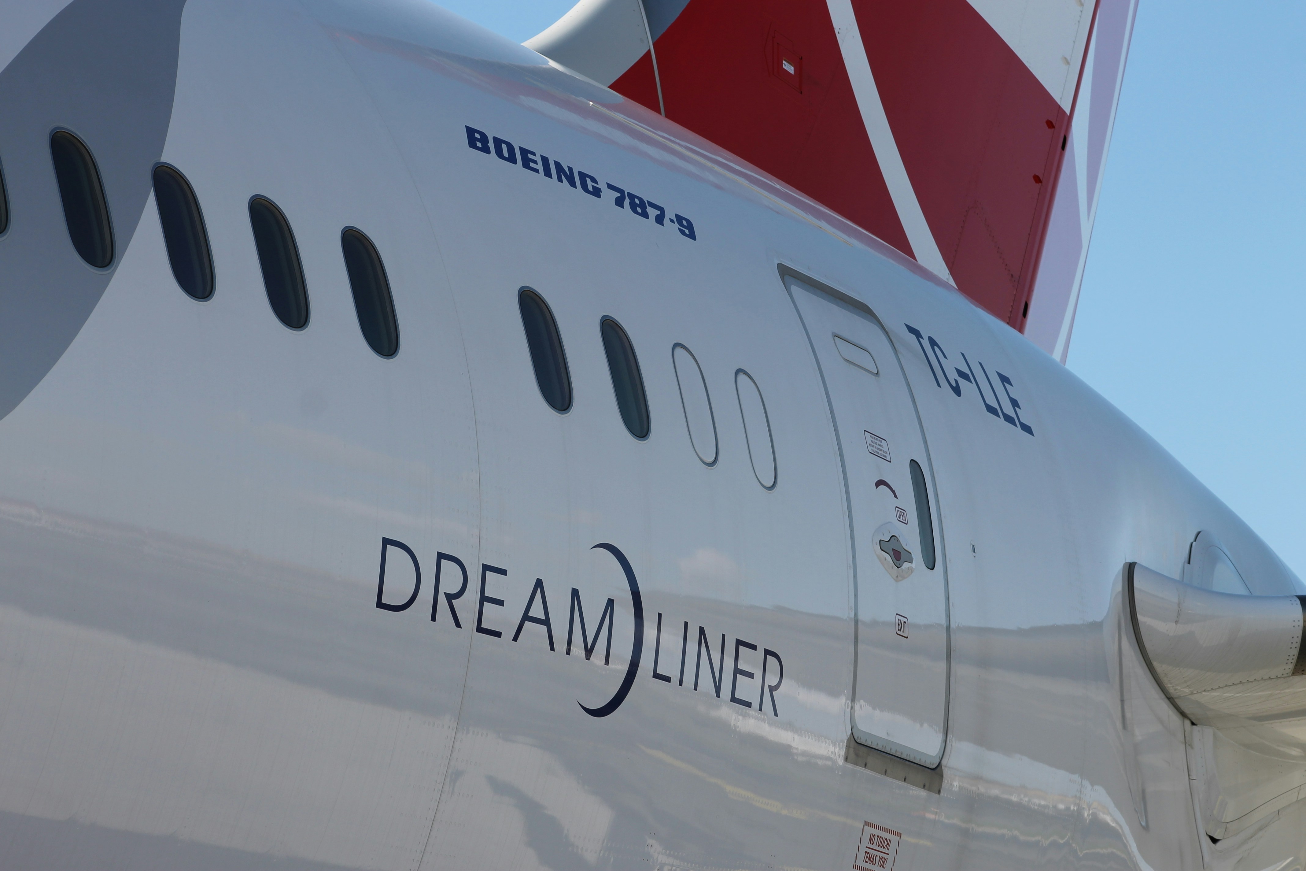 A close-up view of a Turkish Airlines Boeing 787-9 Dreamliner, showing the aircraft fuselage, windows, registration and tail against a clear blue sky.